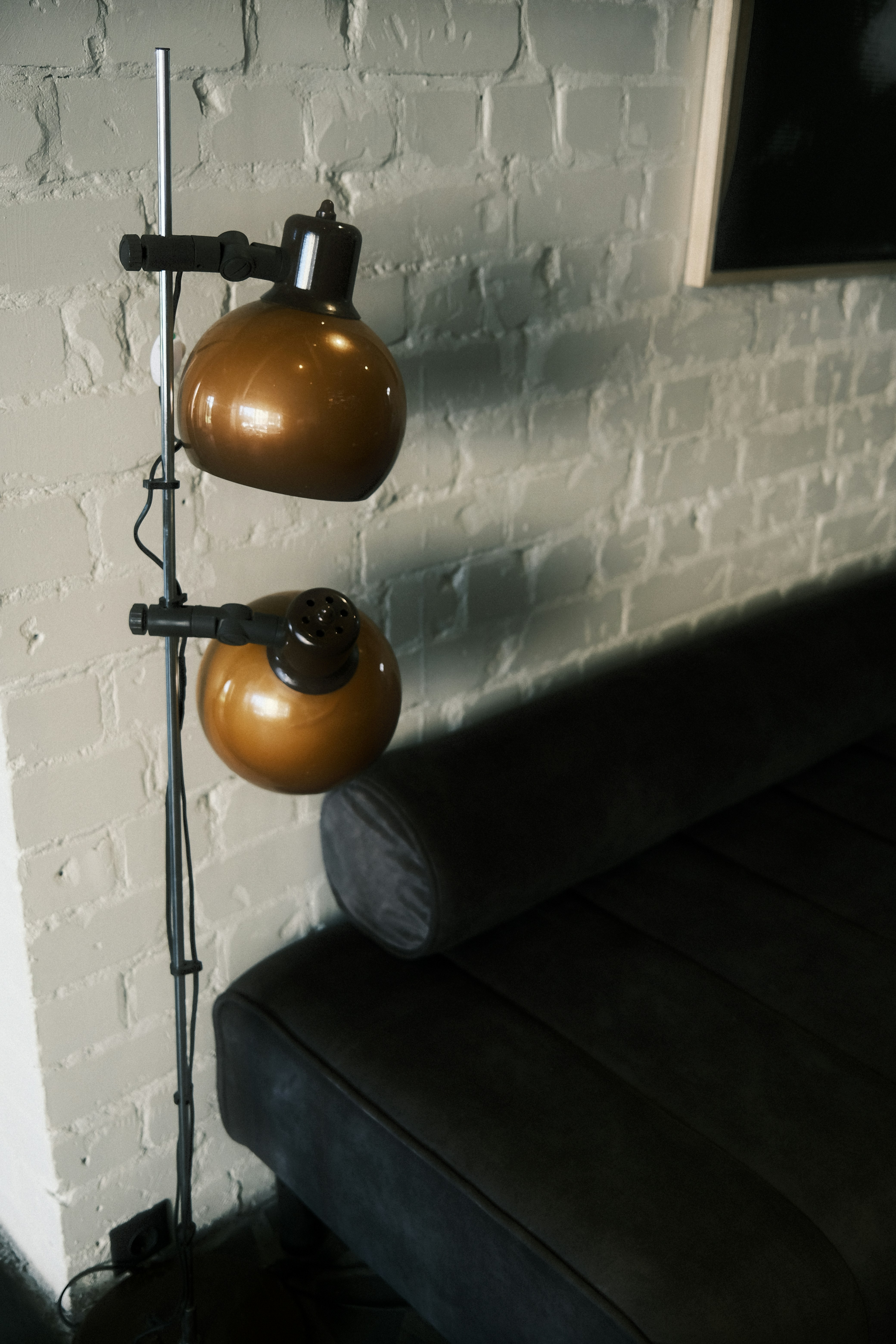 Twin amber lamps on a wall-mount illuminate a brick-walled living nook