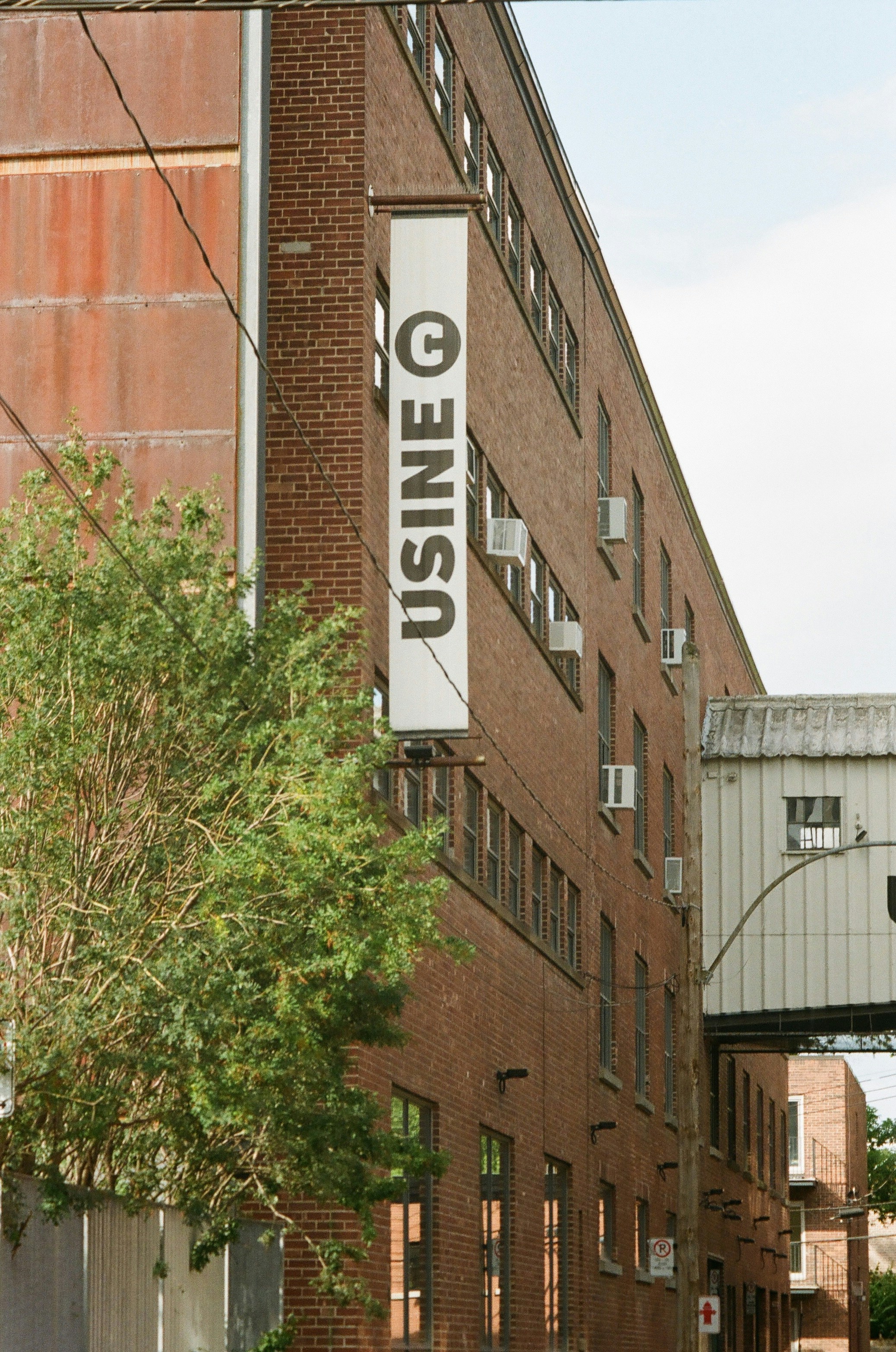 A tall brick building with a sign hanging off the side of it photo ...