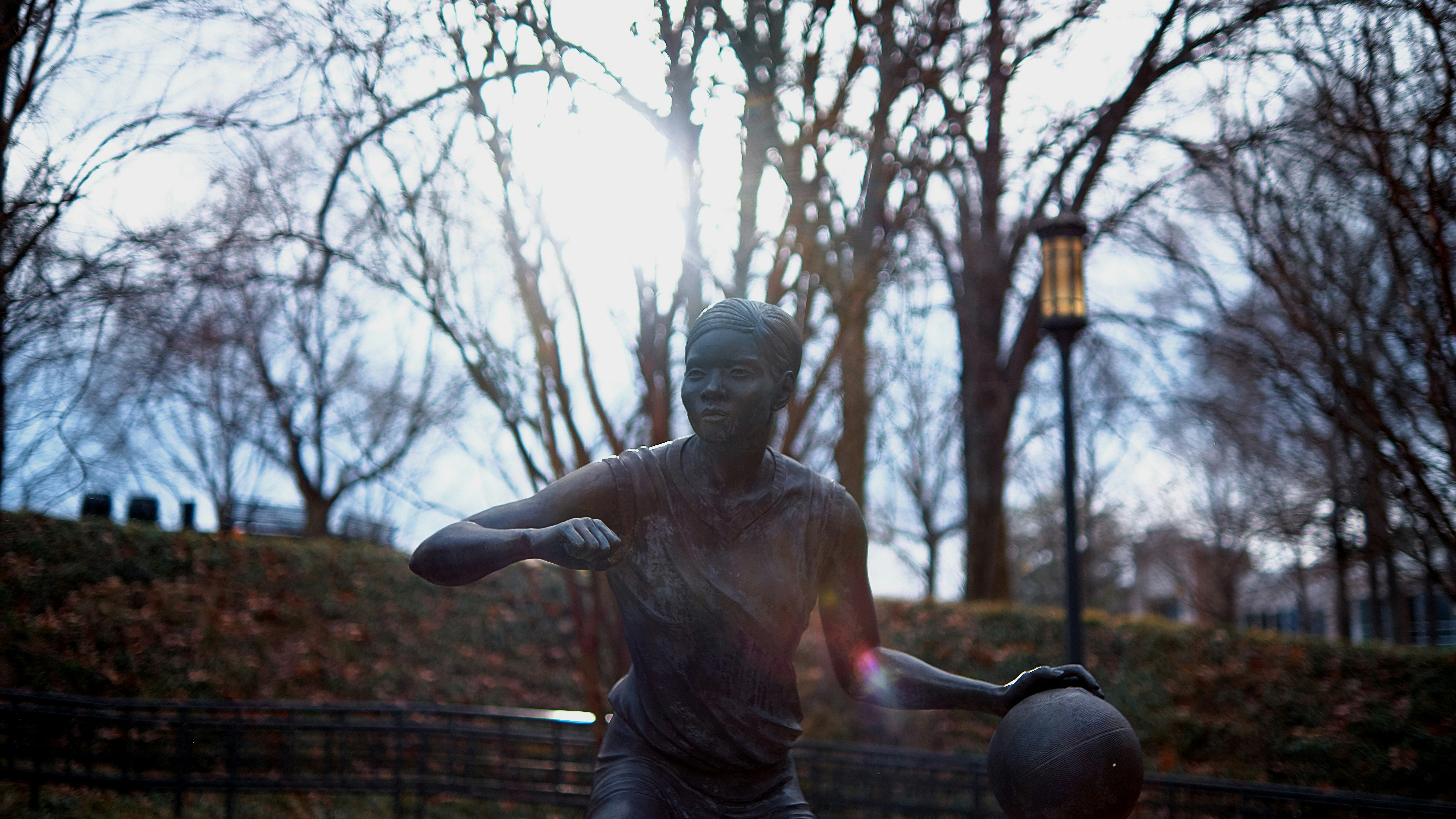 A statue of a man holding a ball in a park photo – Free University of ...