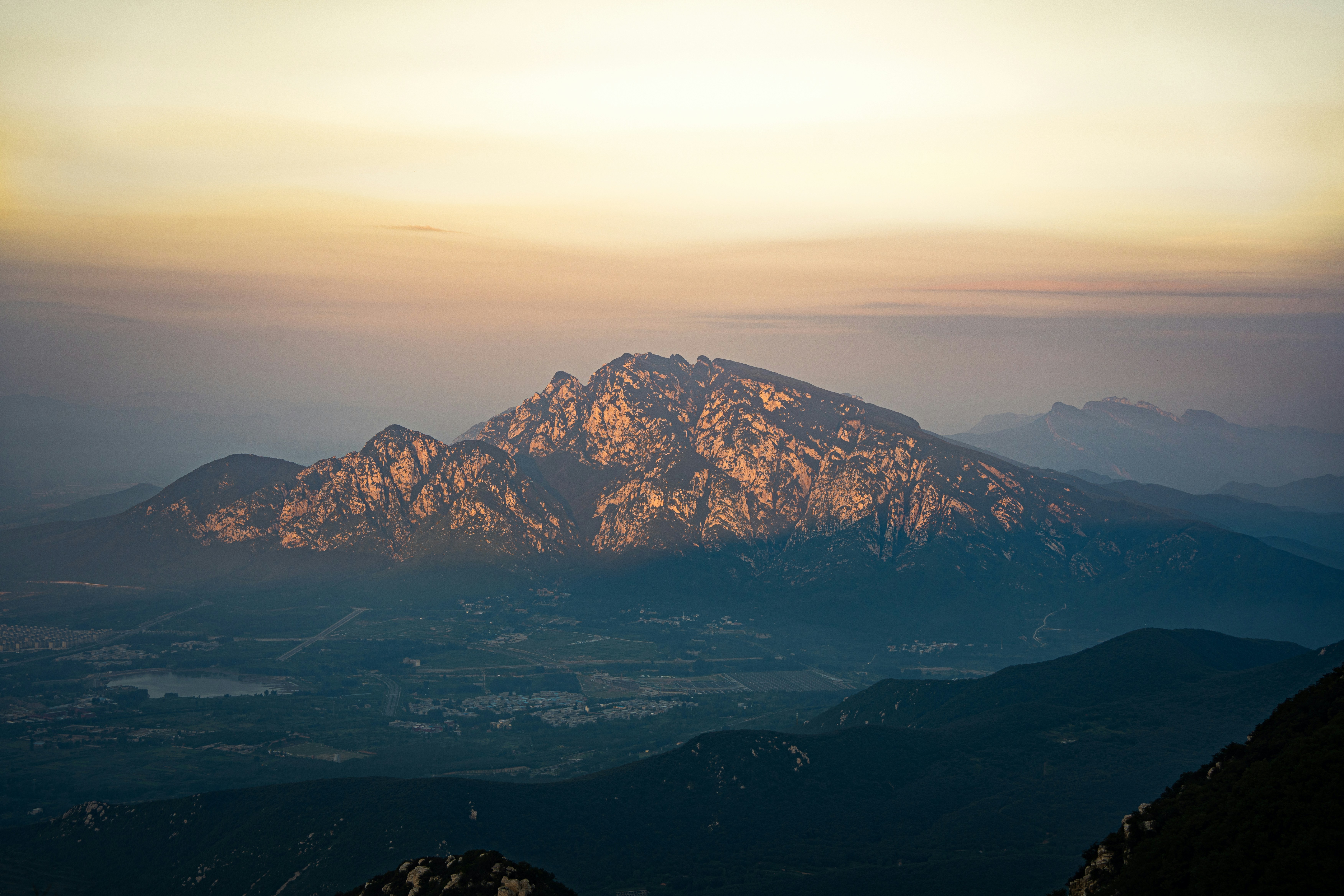 Majestic mountain bathed in soft twilight hues, surrounded by a hazy landscape. The scene captures the serene transition from day to night.