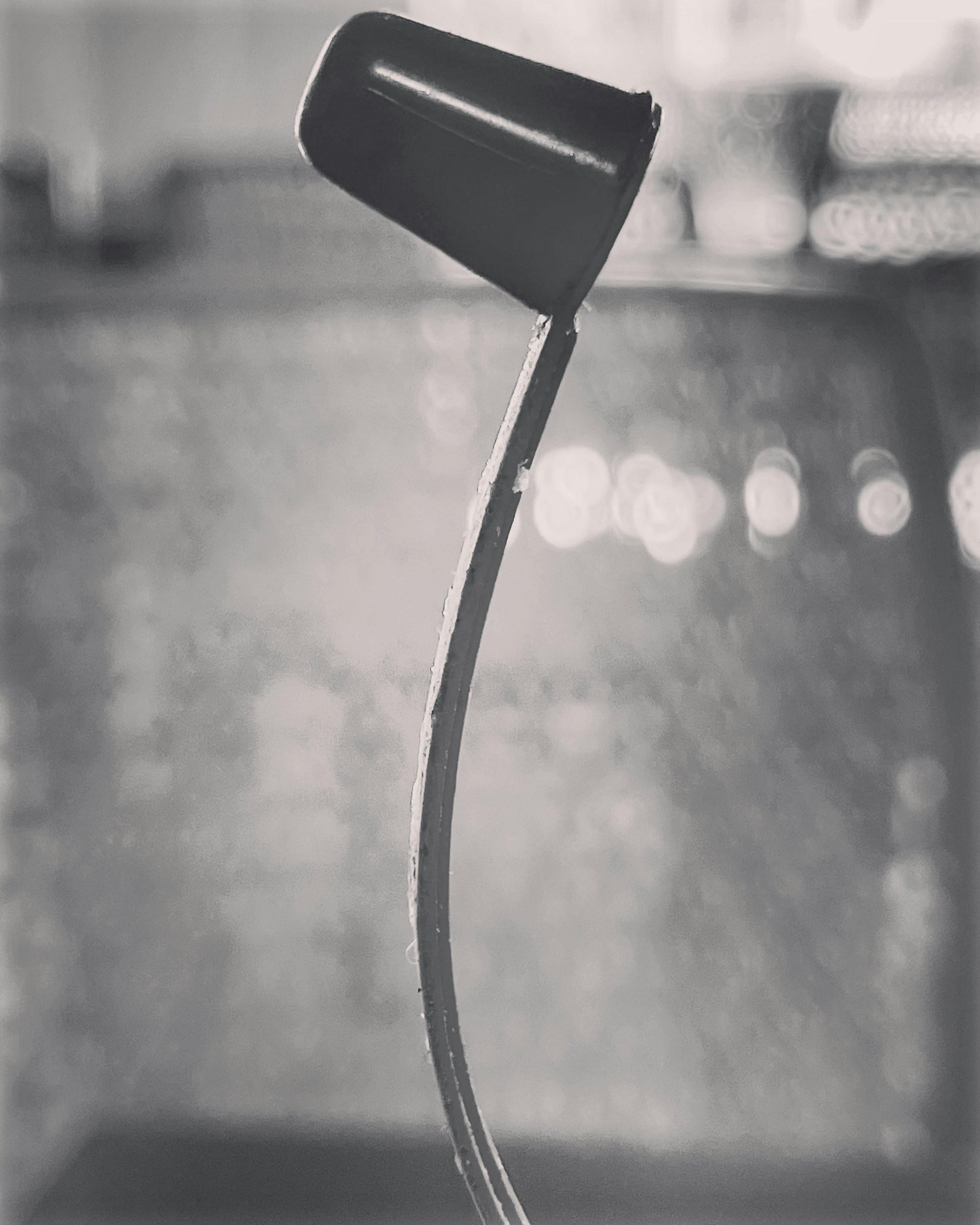 Macro Portrait: A Tiny Mic Head Clinging to a Curved Stem Amid Soft Bokeh