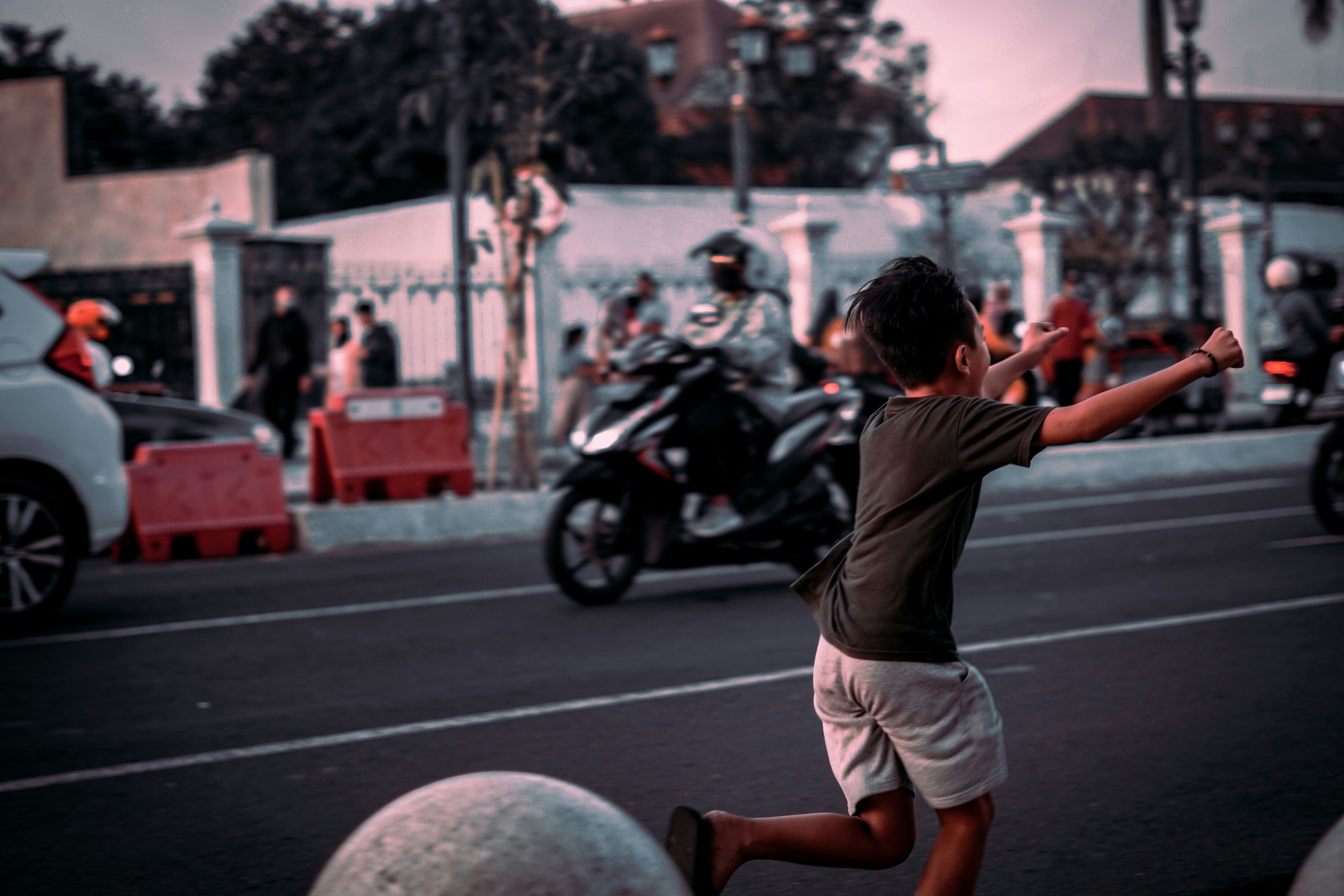 A young boy is playing with a ball in the street photo – Free ...