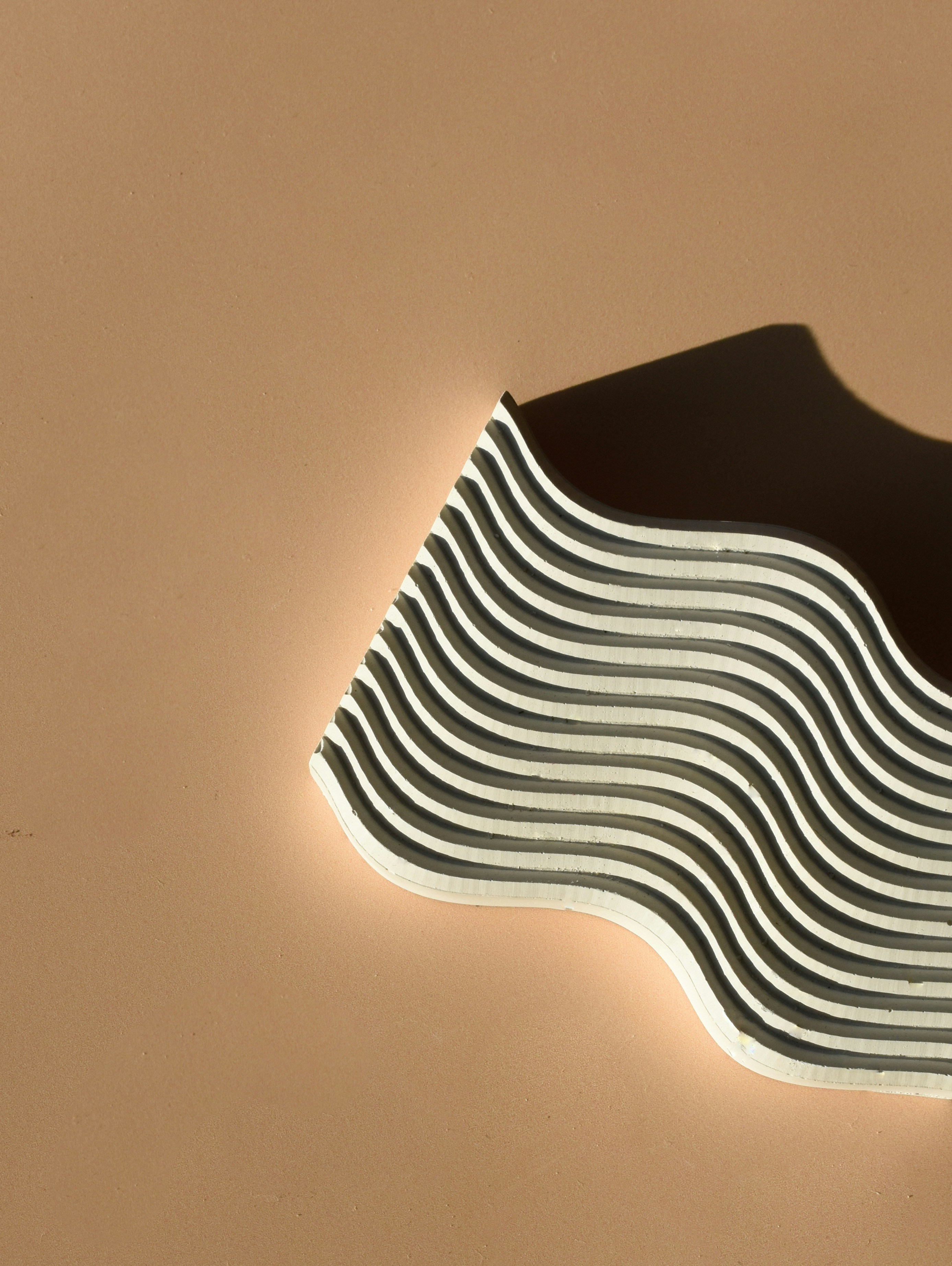 Curved Echoes: Sculpted Light on a Peach Wall