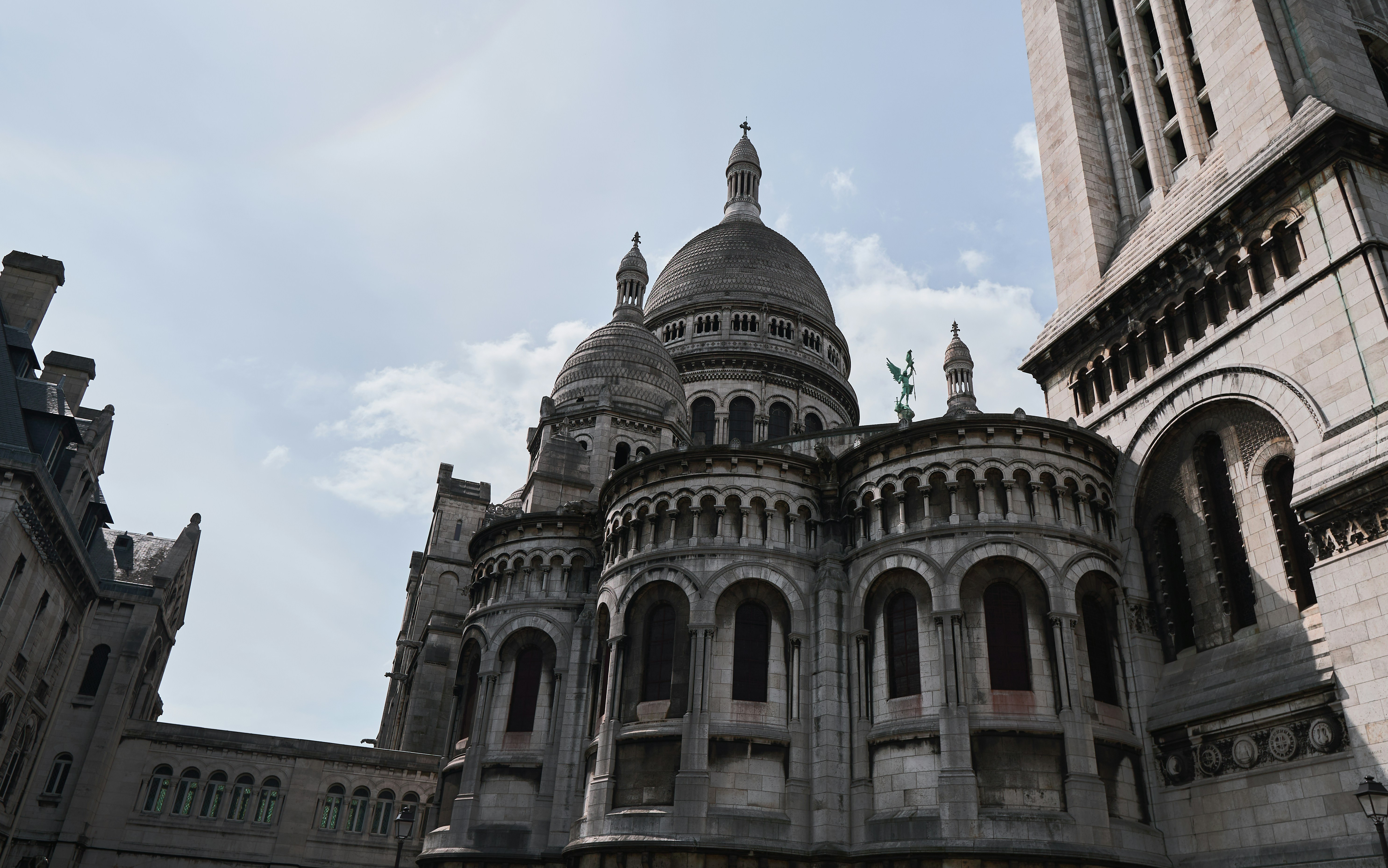 Ornate domes and intricate stonework of Sacré-Cœur Basilica under a clear sky.