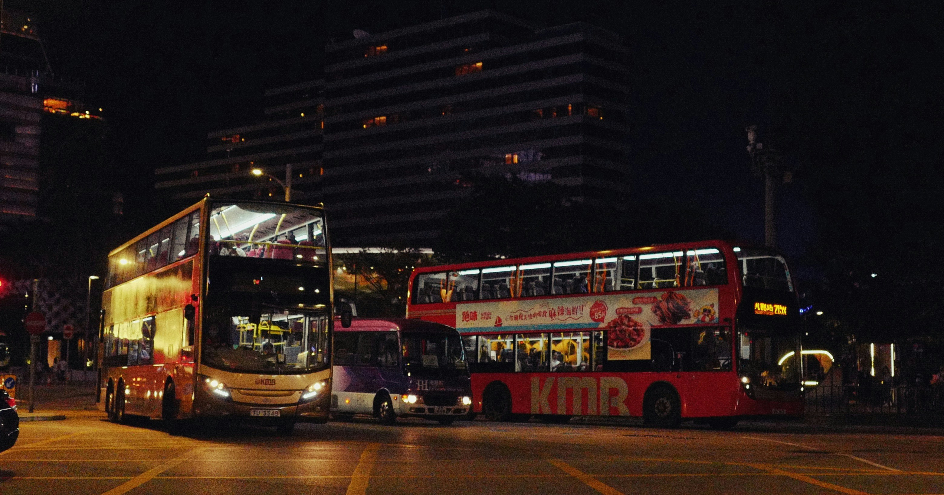 A double decker bus driving down a street at night photo – Free Car ...
