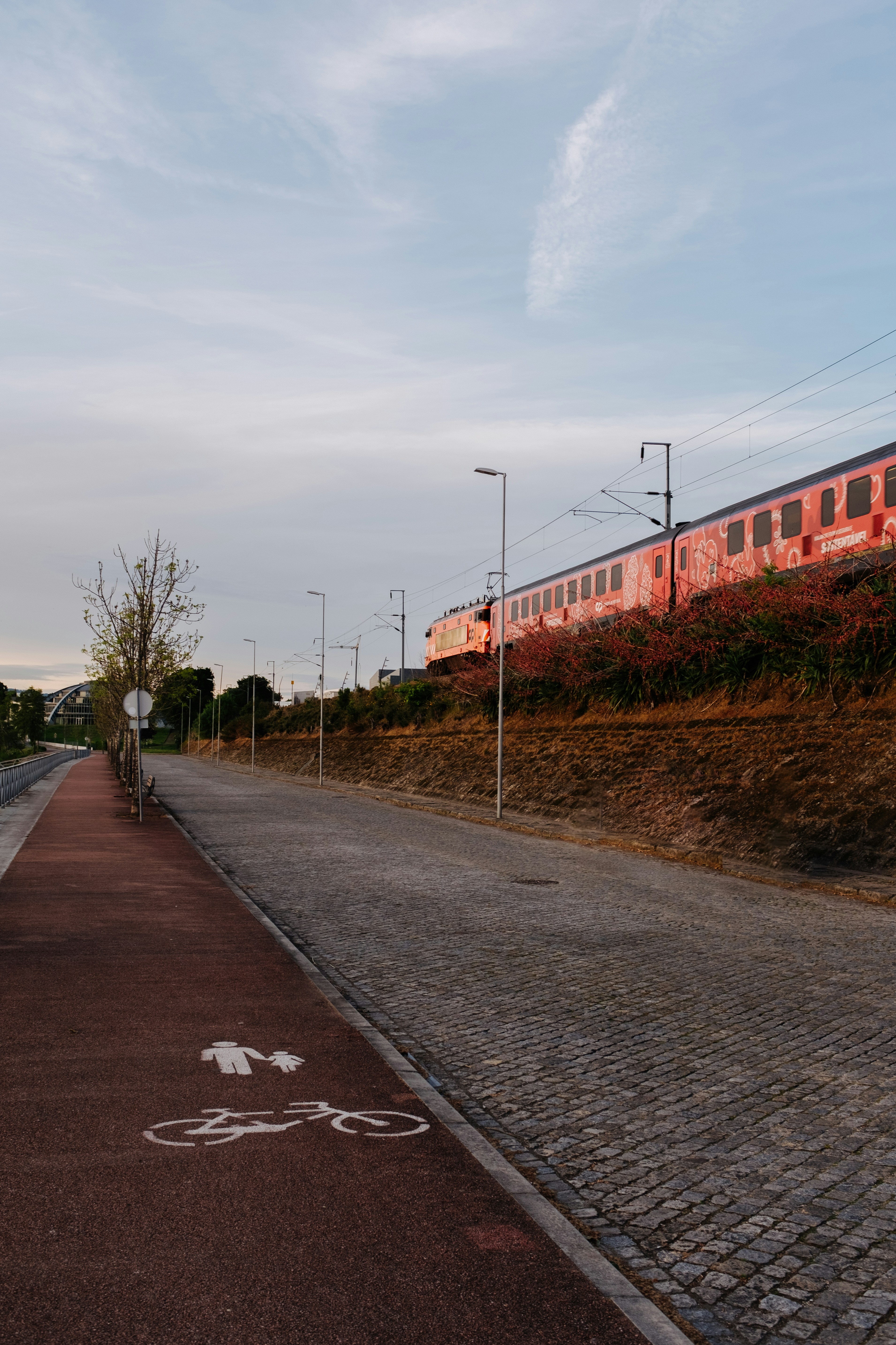 A red train traveling down train tracks next to a road photo – Free ...