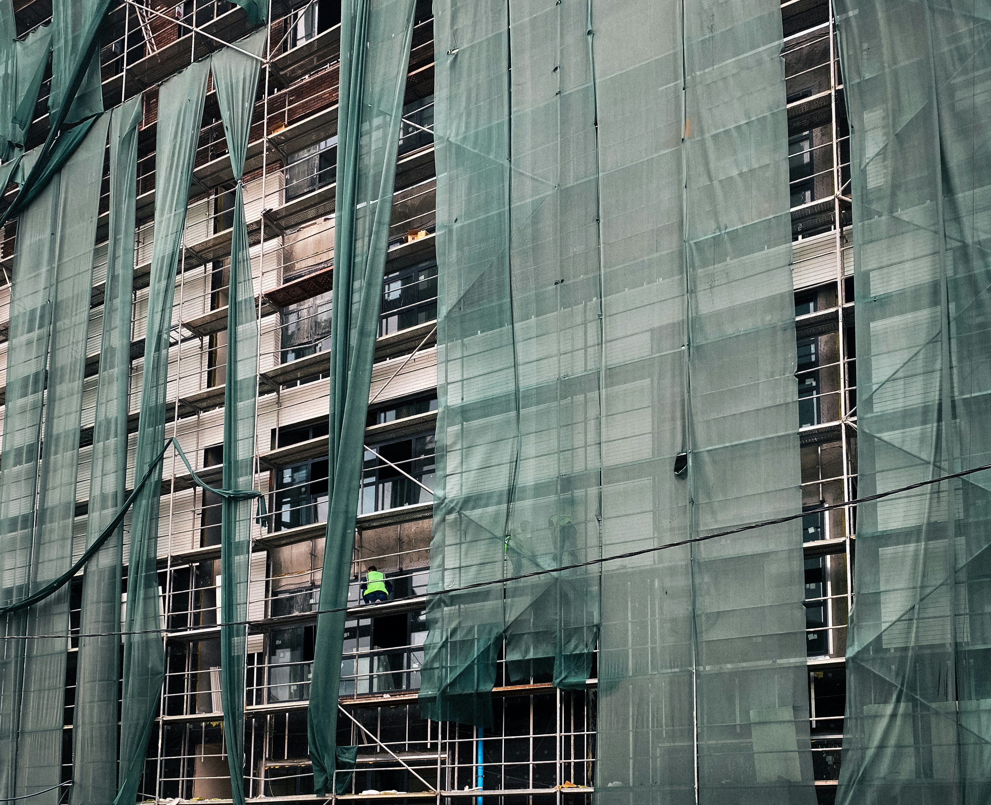 Veiled Facade: Green Construction Netting Framing a High-Rise