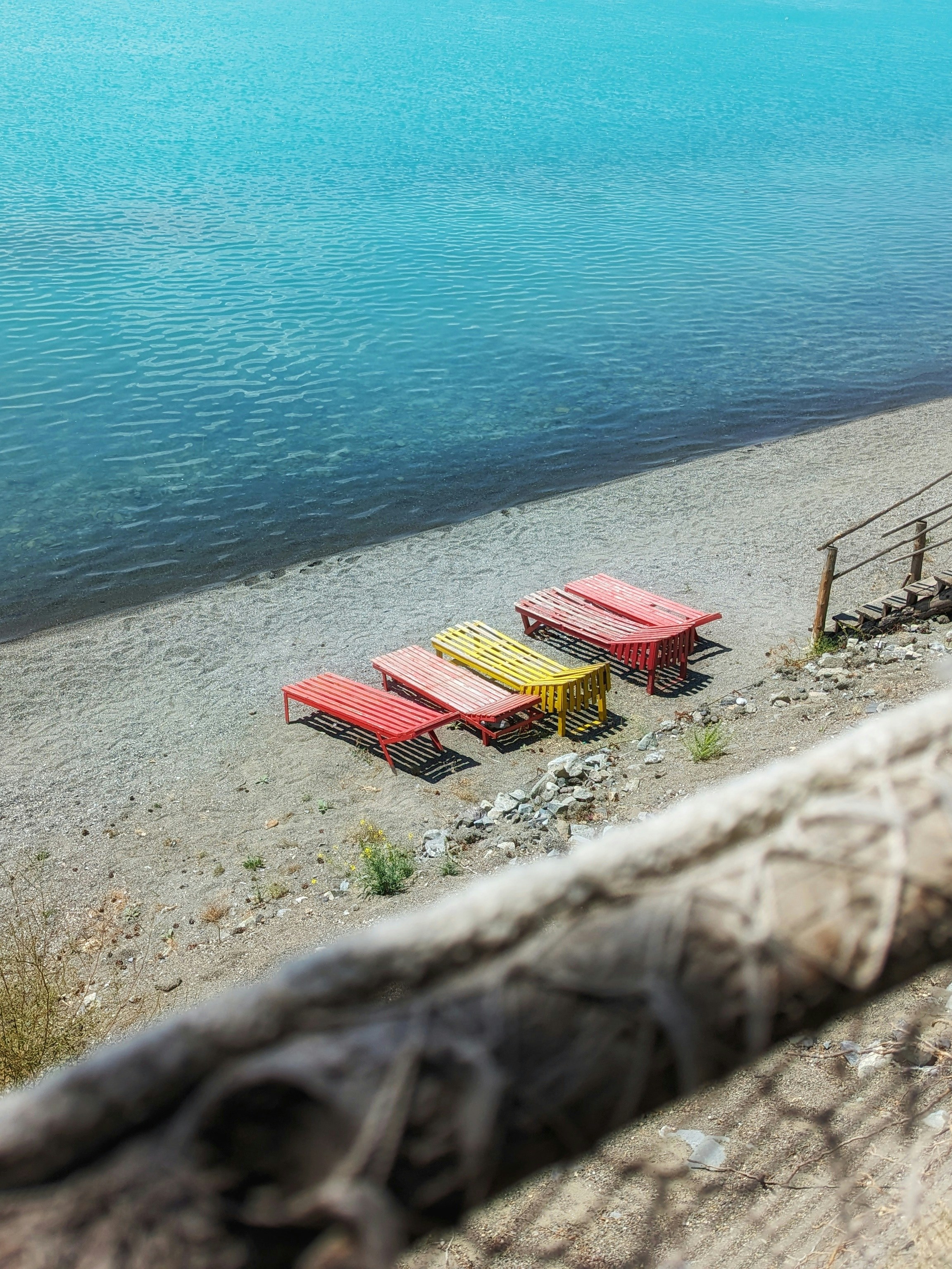 Sunlit Row of Red and Yellow Loungers by Turquoise Waters