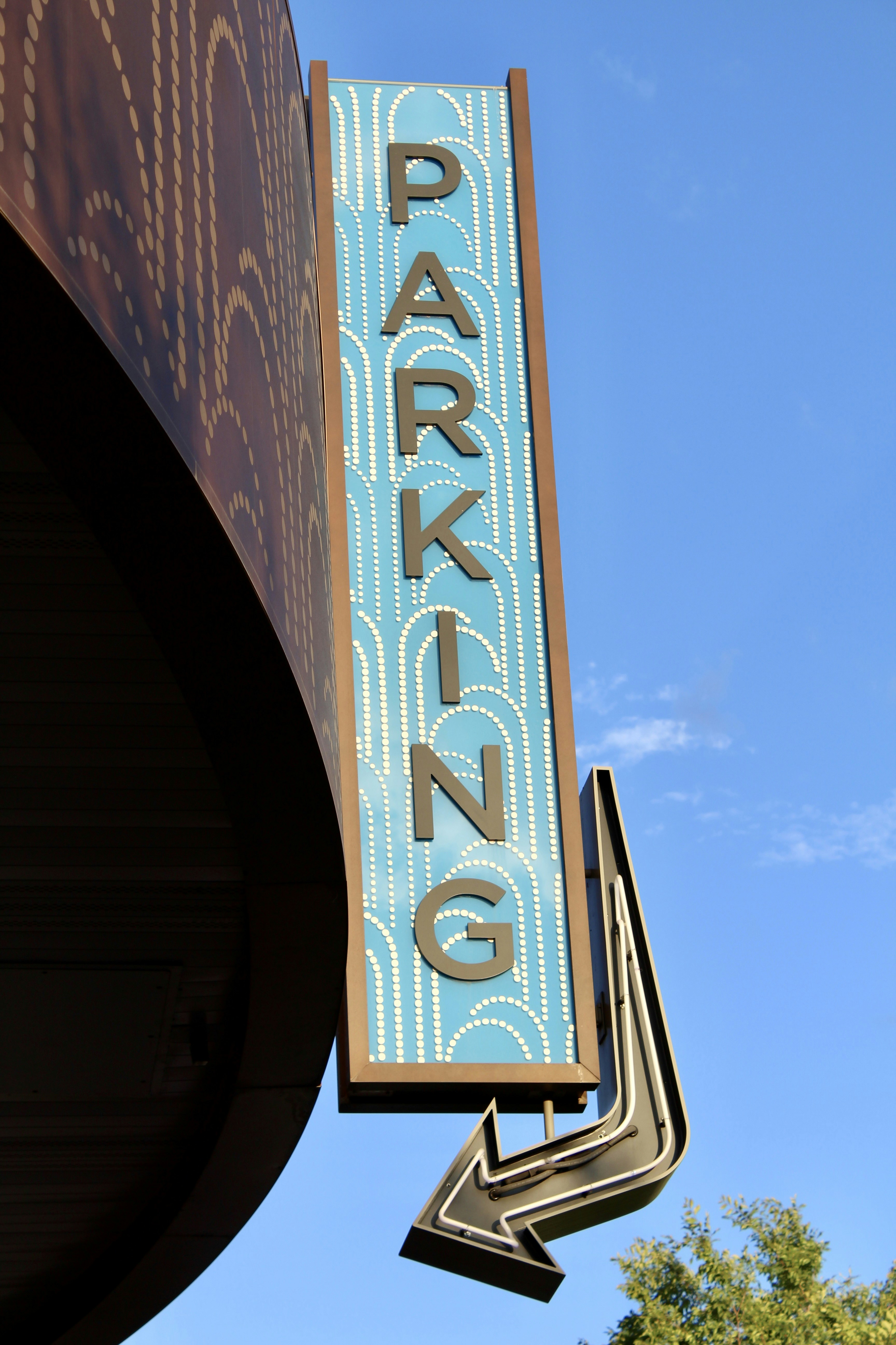 PARKING: A Vertical Blue Sign with Art Deco Panels Against a Clear Sky