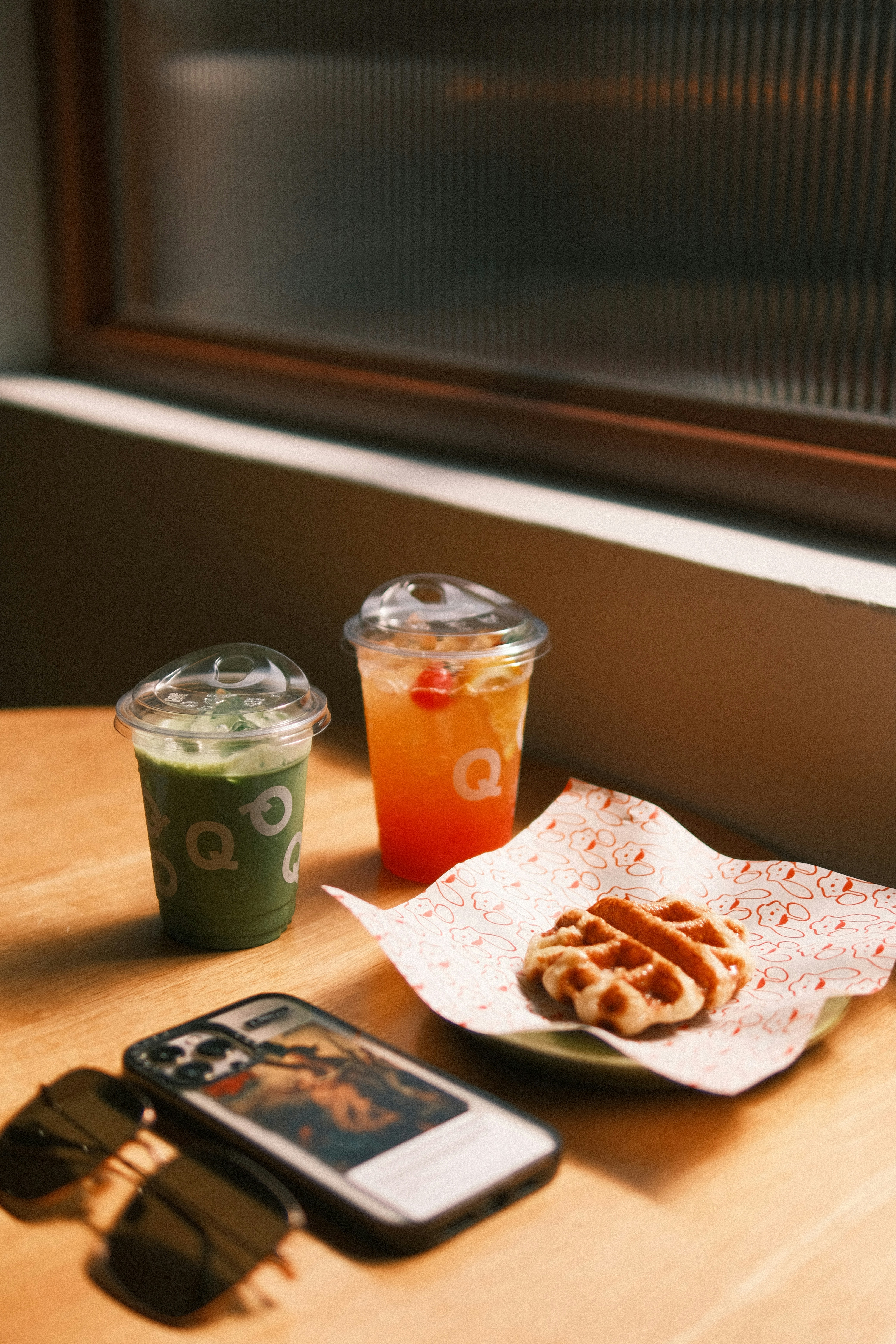 Sunlit Café Spread: Green Matcha and Citrus Iced Tea Beside a Waffle Pastry
