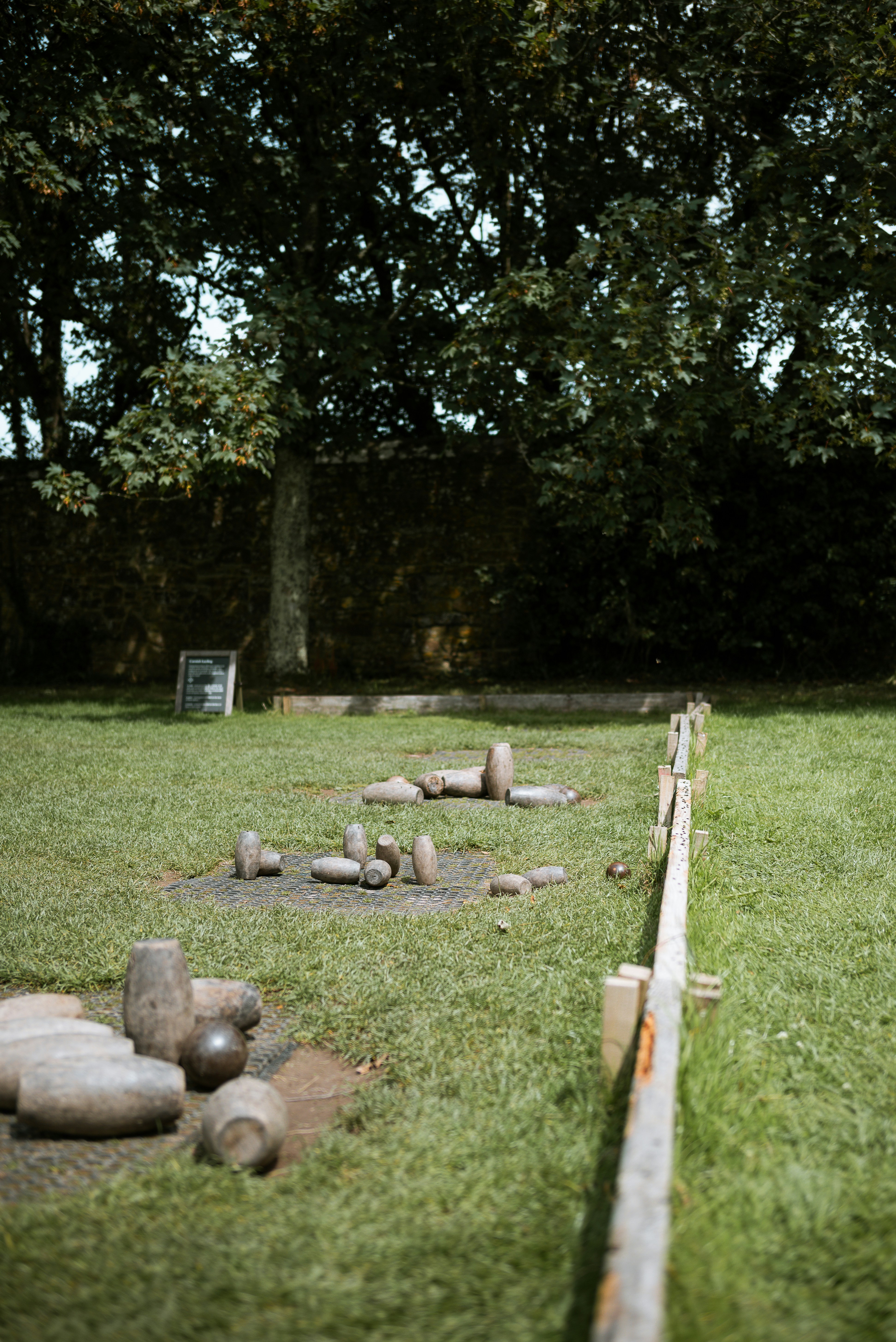 Stone Arcade on a Sunlit Lawn: Quiet Geometry by the Fence