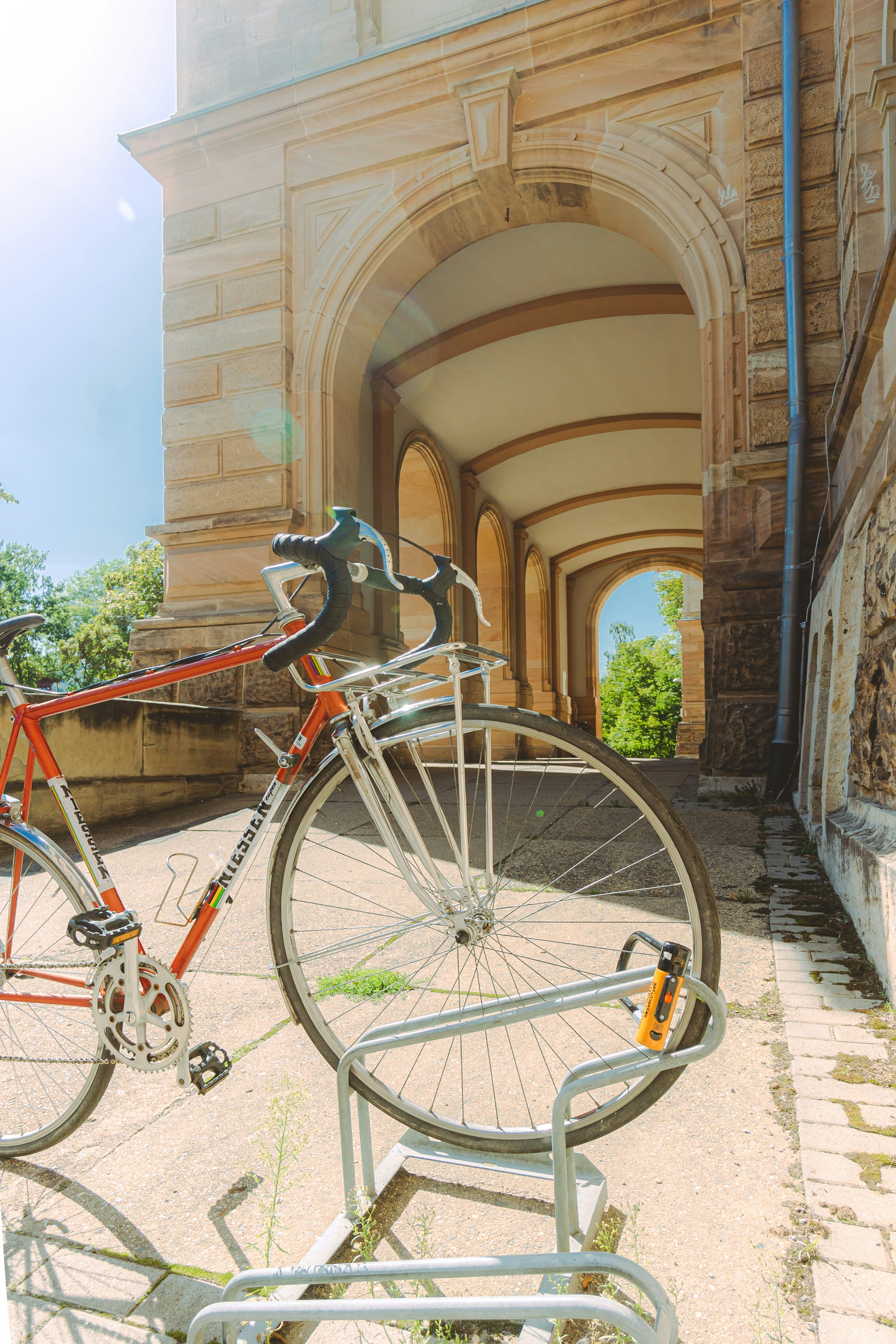 Sunlit Arcades and a Vintage Red Road Bike in Quiet Morning