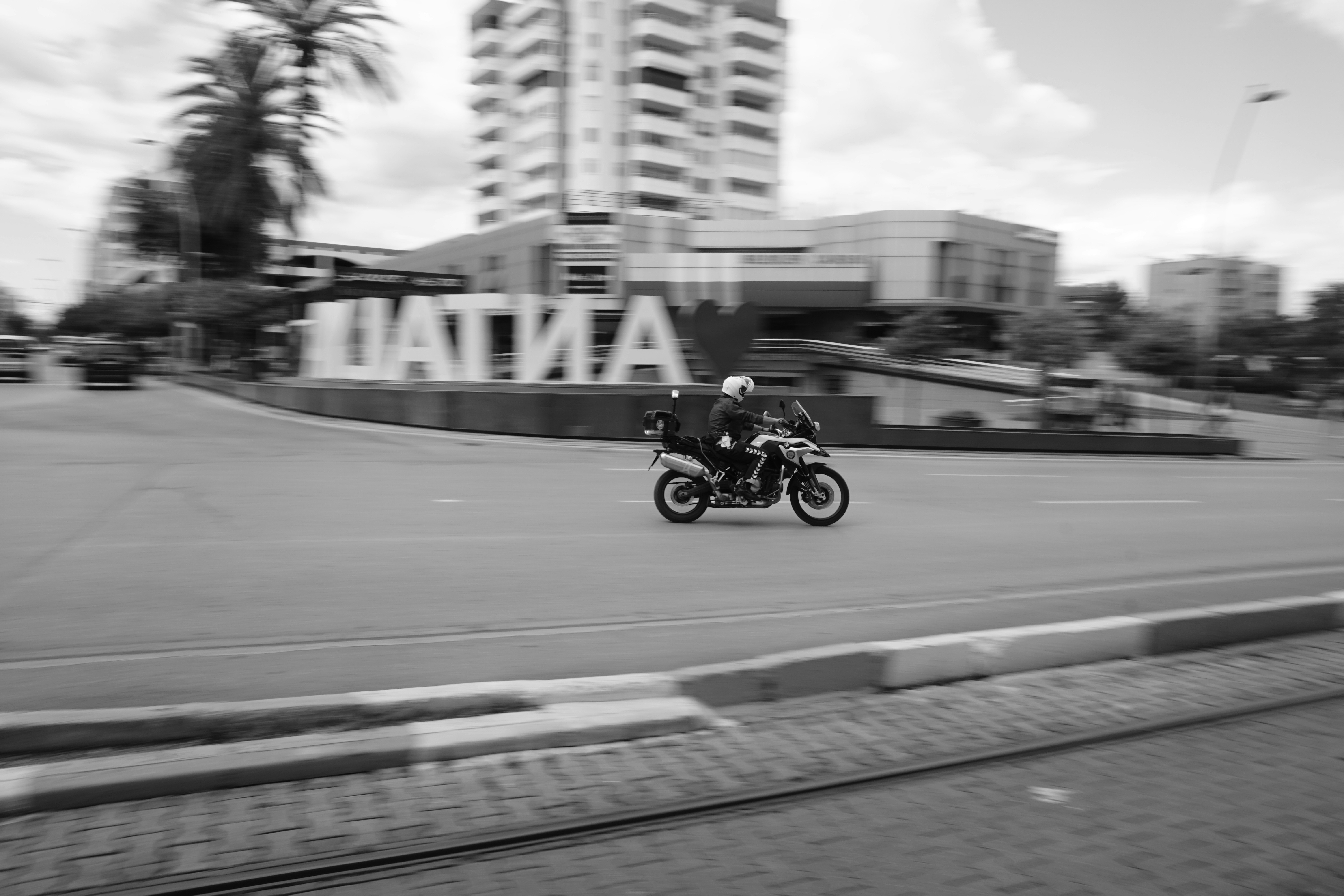 Monochrome Momentum: A lone motorcyclist in a grayscale city square