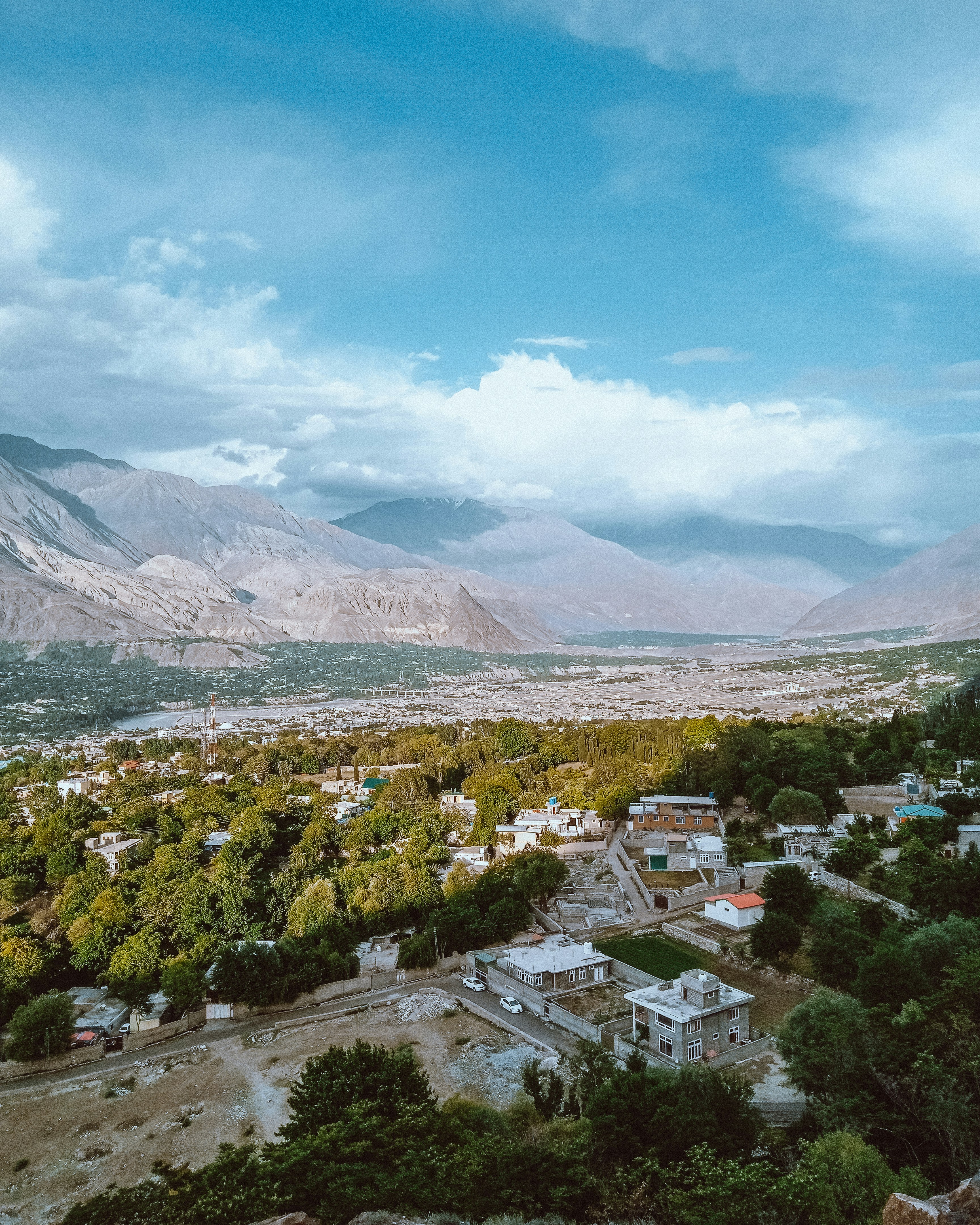 Aerial view of a valley town nestled among trees with rugged mountains rising in the distance.