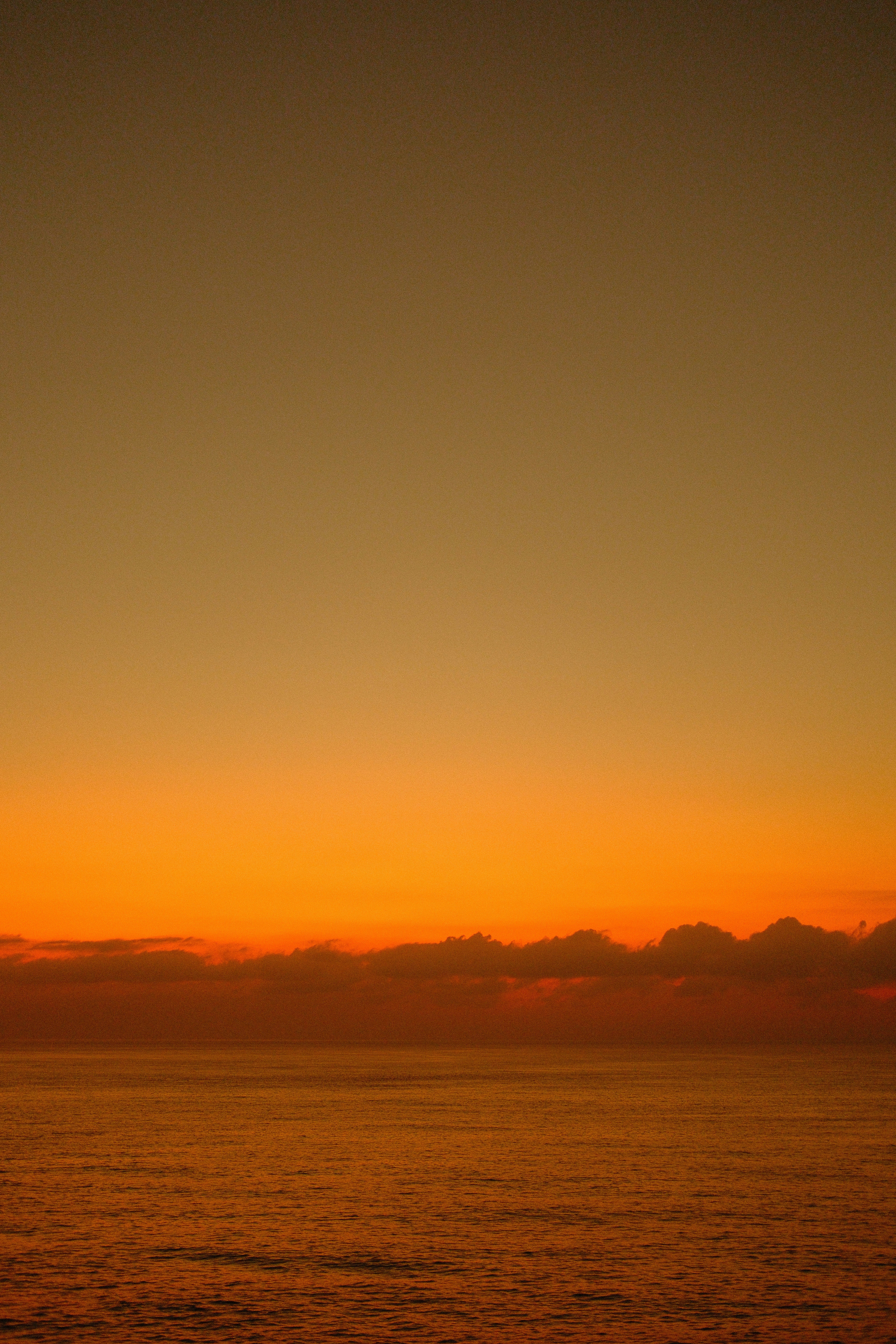 a plane flying over a body of water at sunset