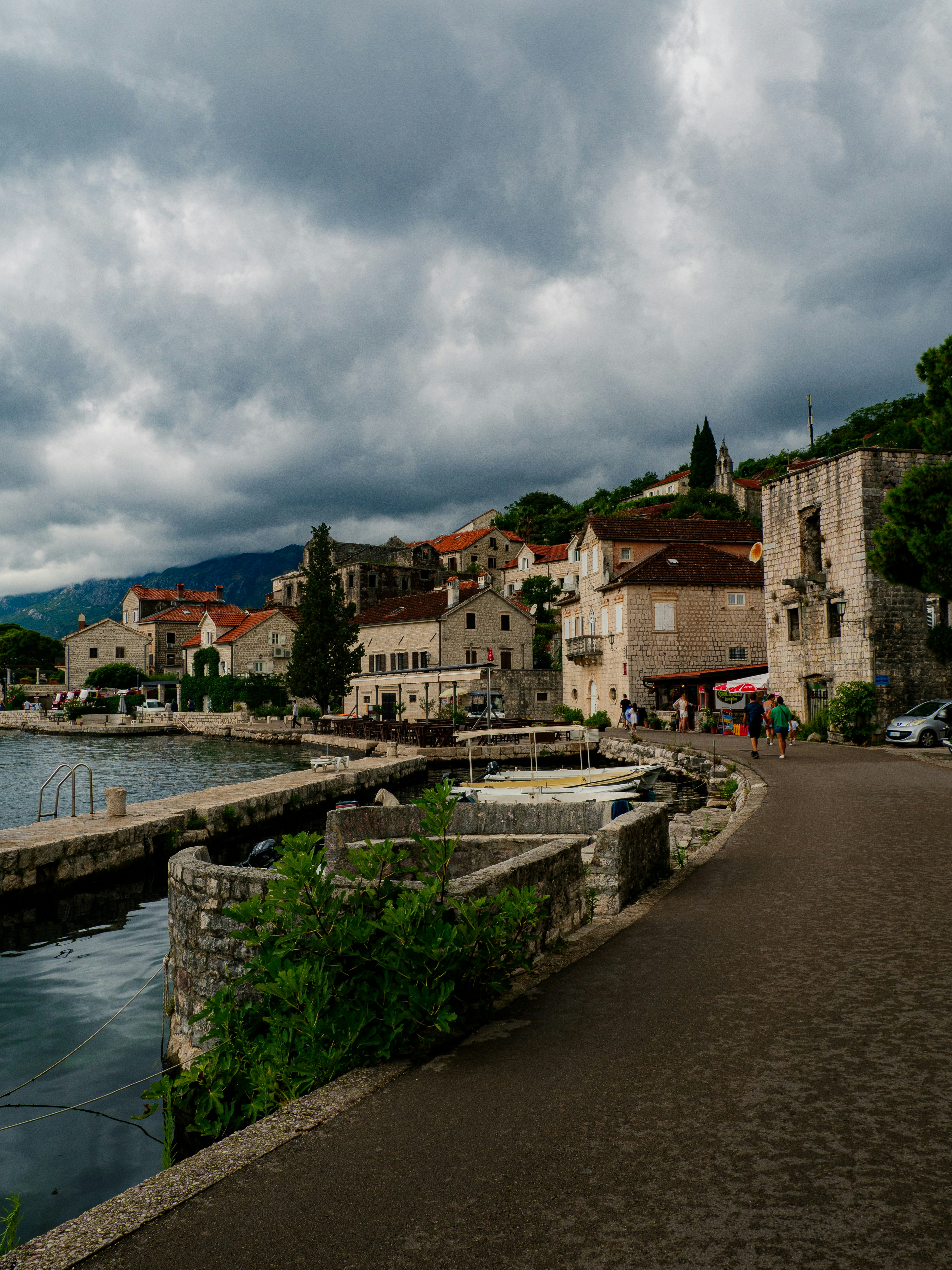 Quaywalk at Dusk: Stone Facades, Boats, and a Brooding Mediterranean Sky