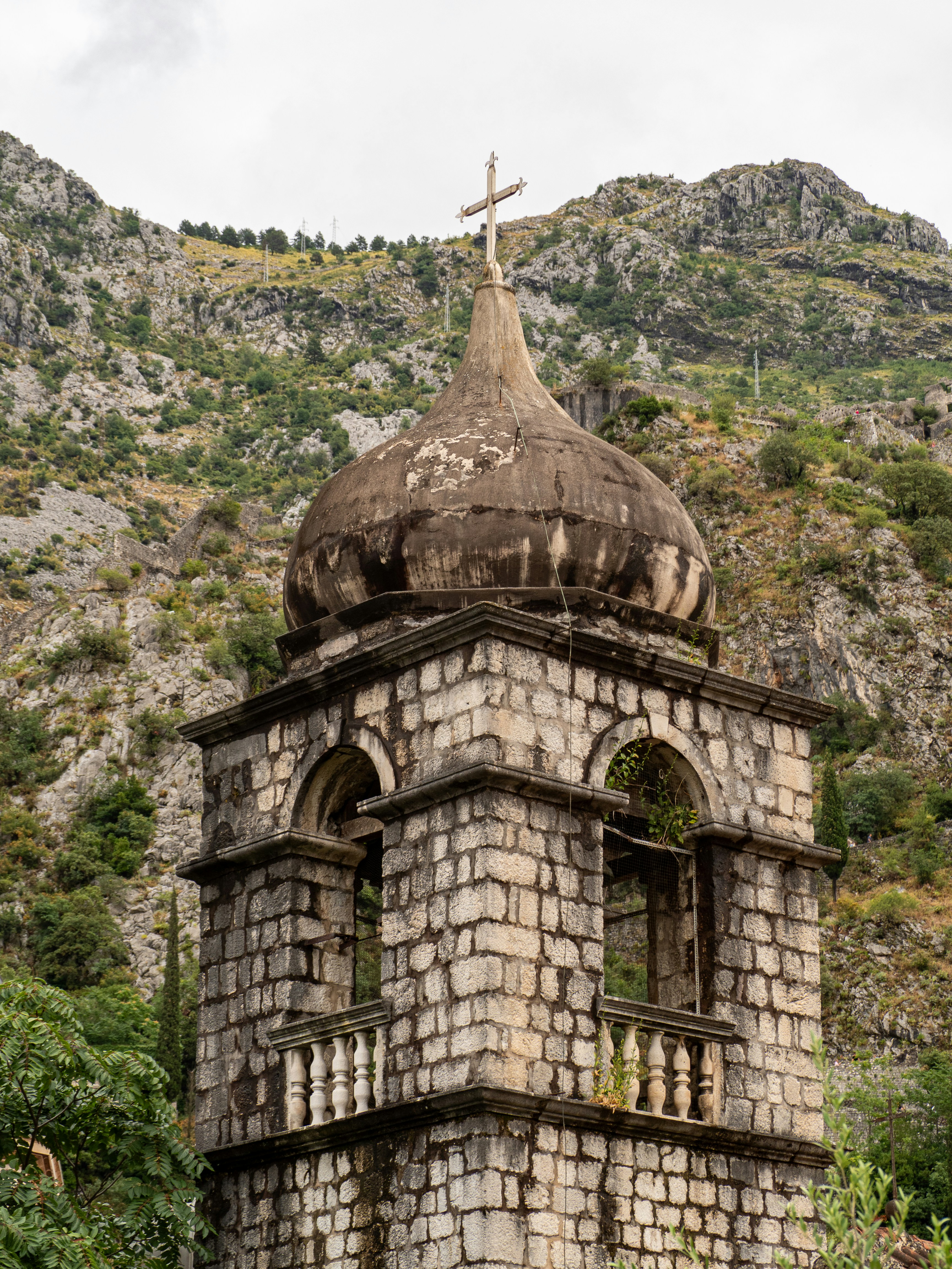 Dome and Cross: Weathered Bell Tower Rising from a Rocky Crag