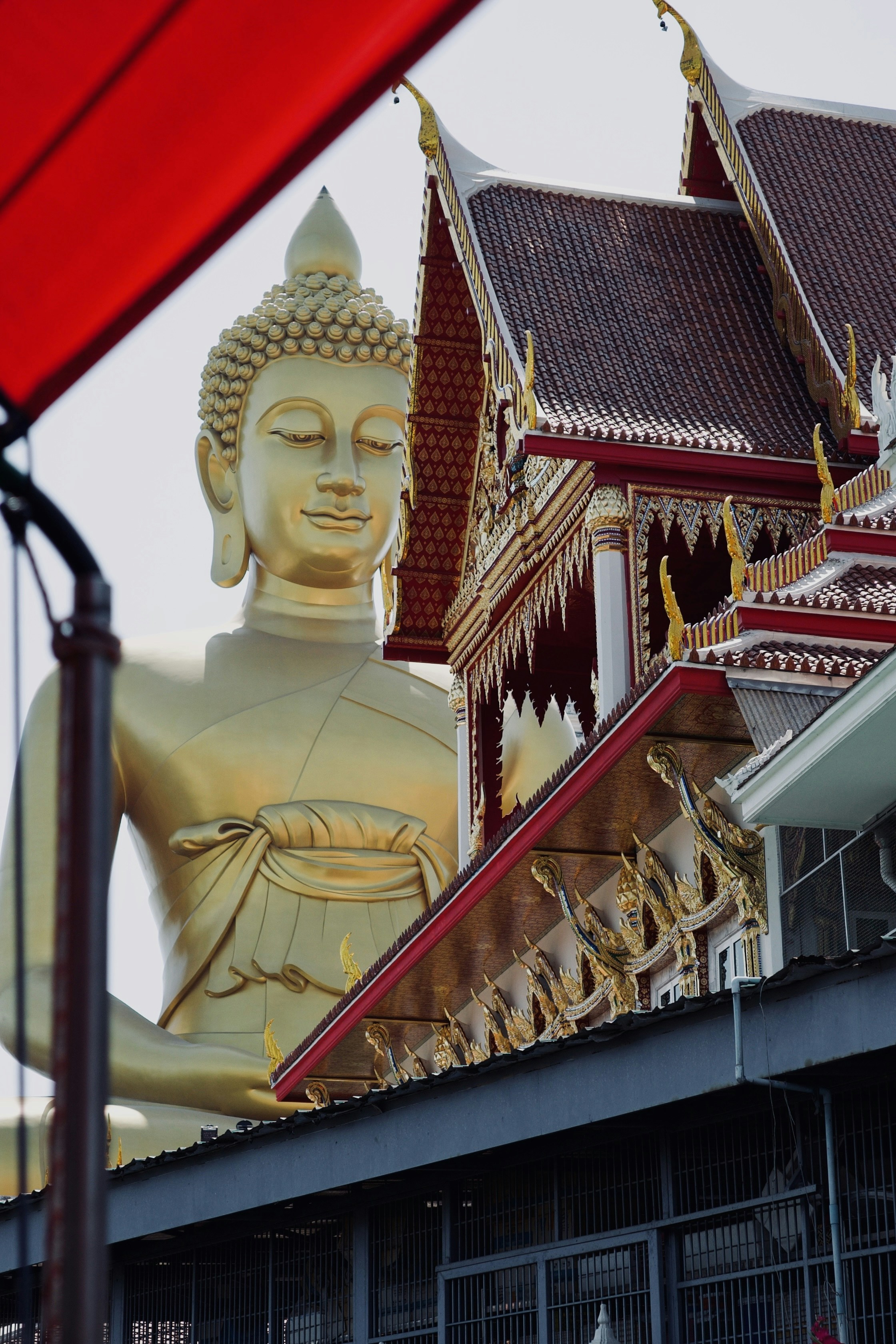 Majestic golden Buddha statue towering over intricately designed temple architecture, showcasing a blend of spirituality and artistry.