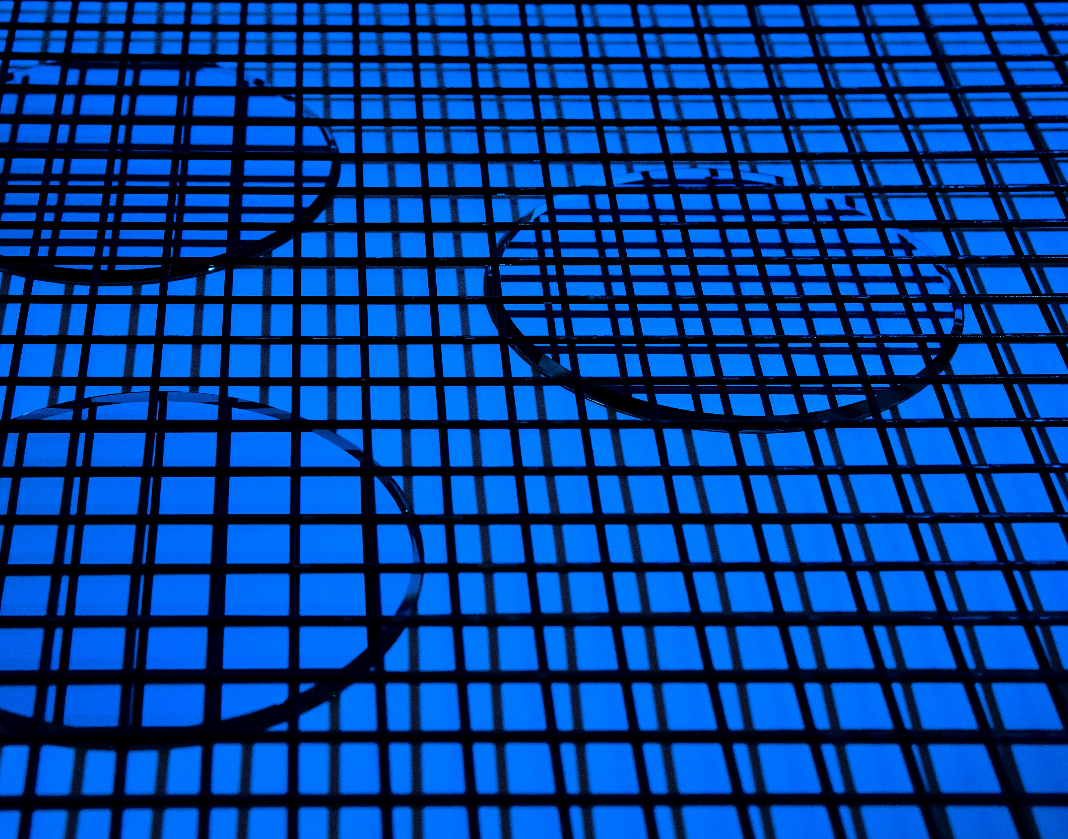 Abstract blue grid pattern with circular reflections creating a layered effect.