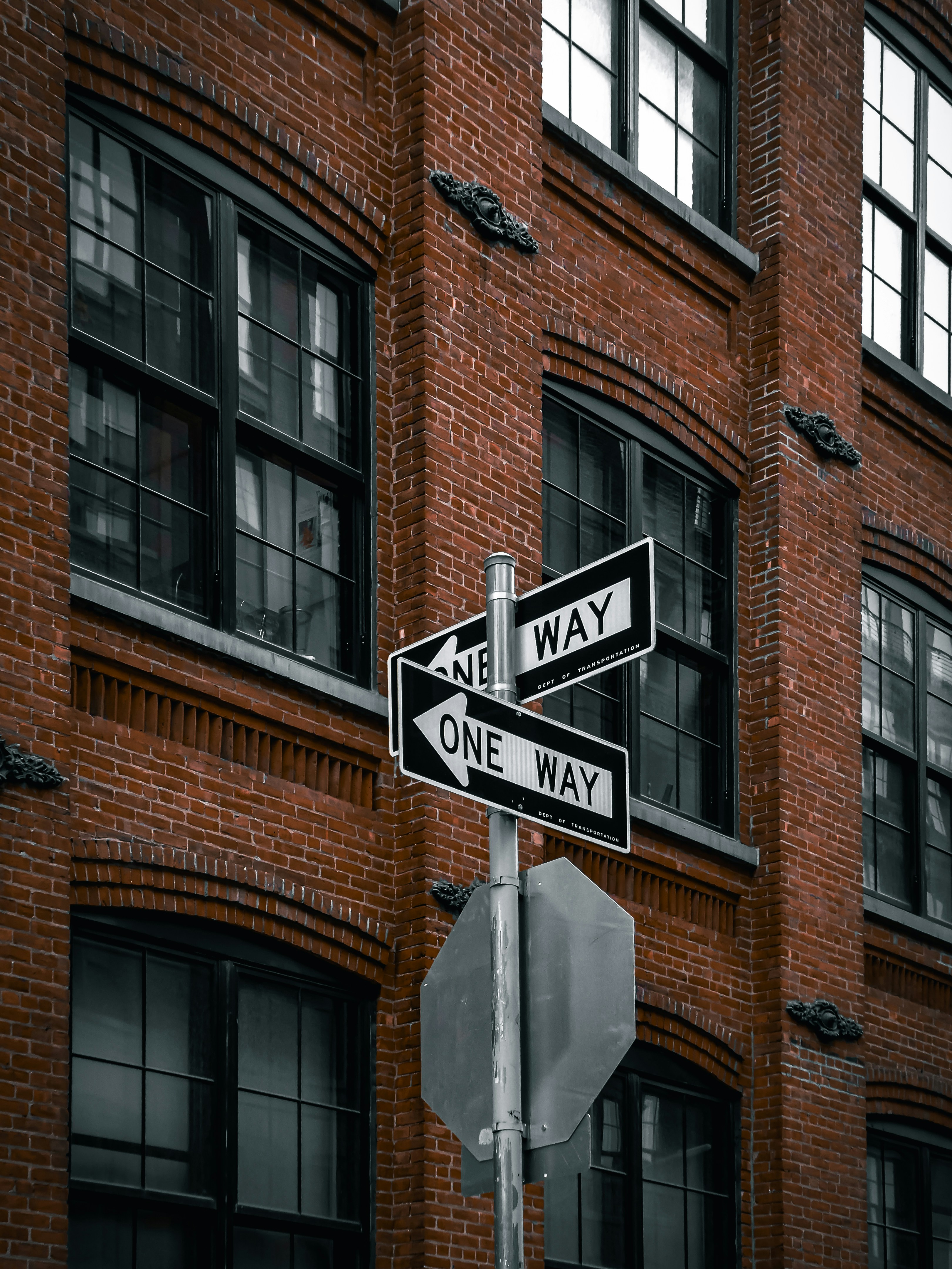 Two street signs on a pole in front of a brick building photo – Free ...