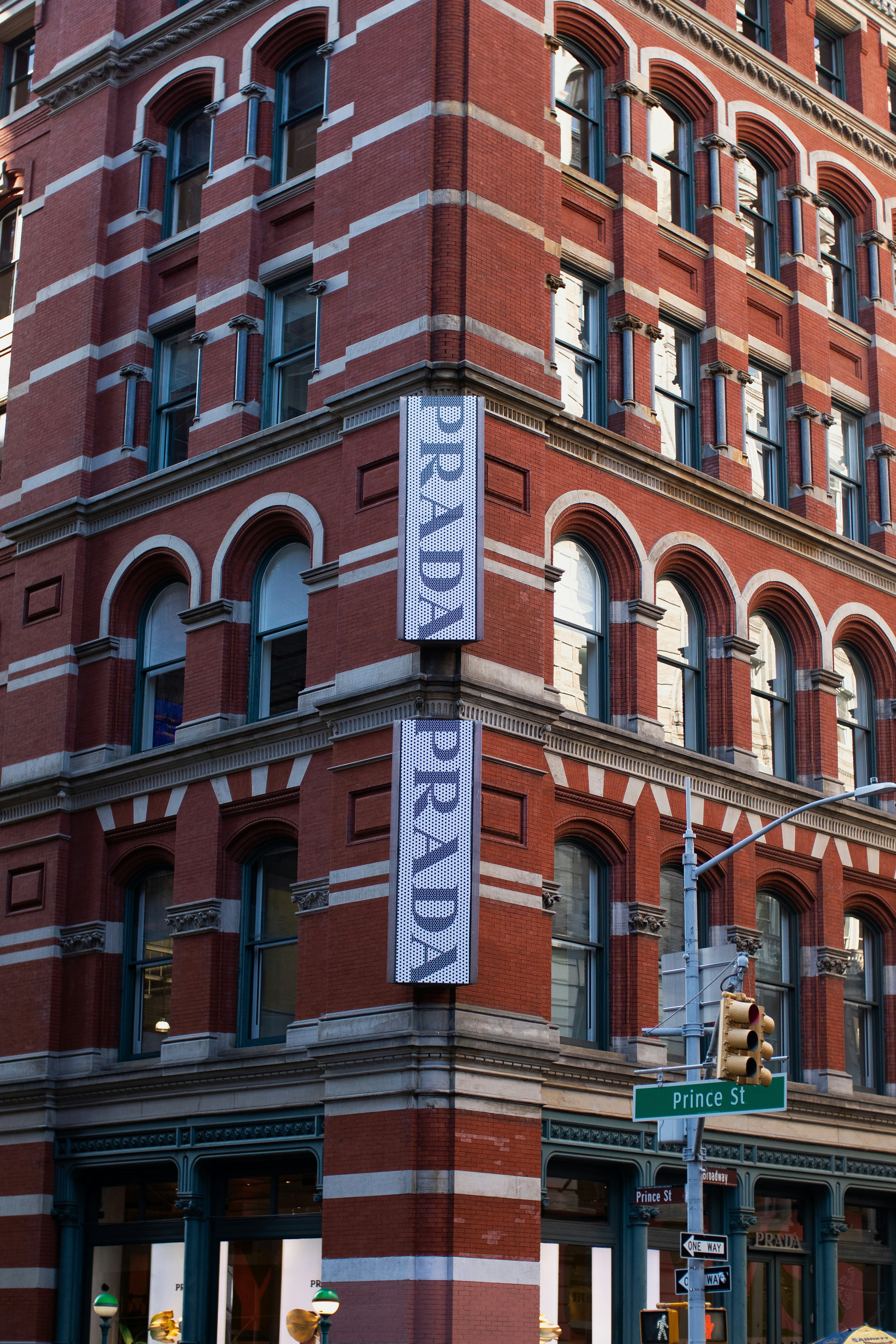 Prada Corner: Vertical Banners Rise on a Red Brick Facade