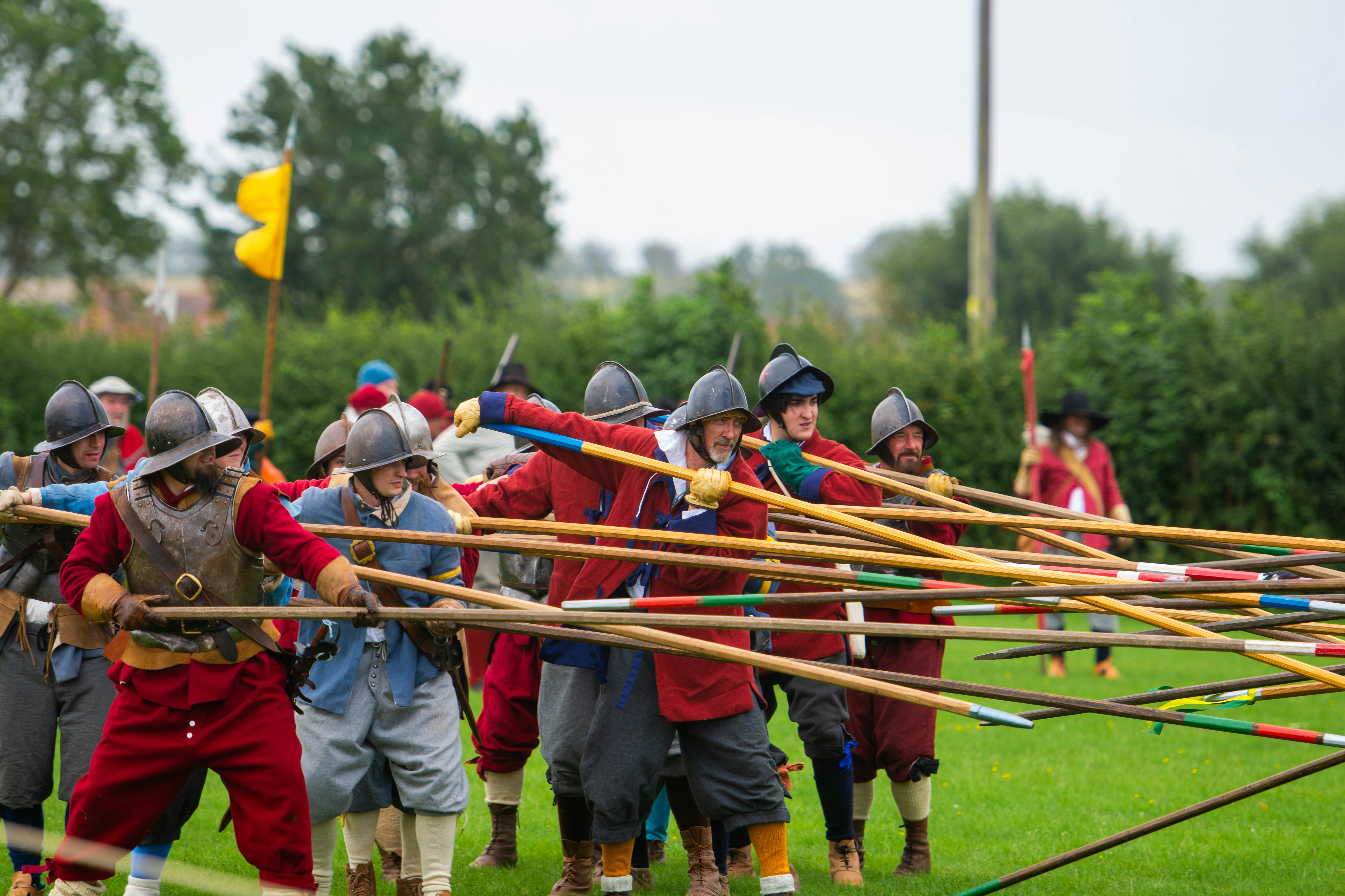 A group of men in uniforms holding up wooden arrows photo – Free Worker ...