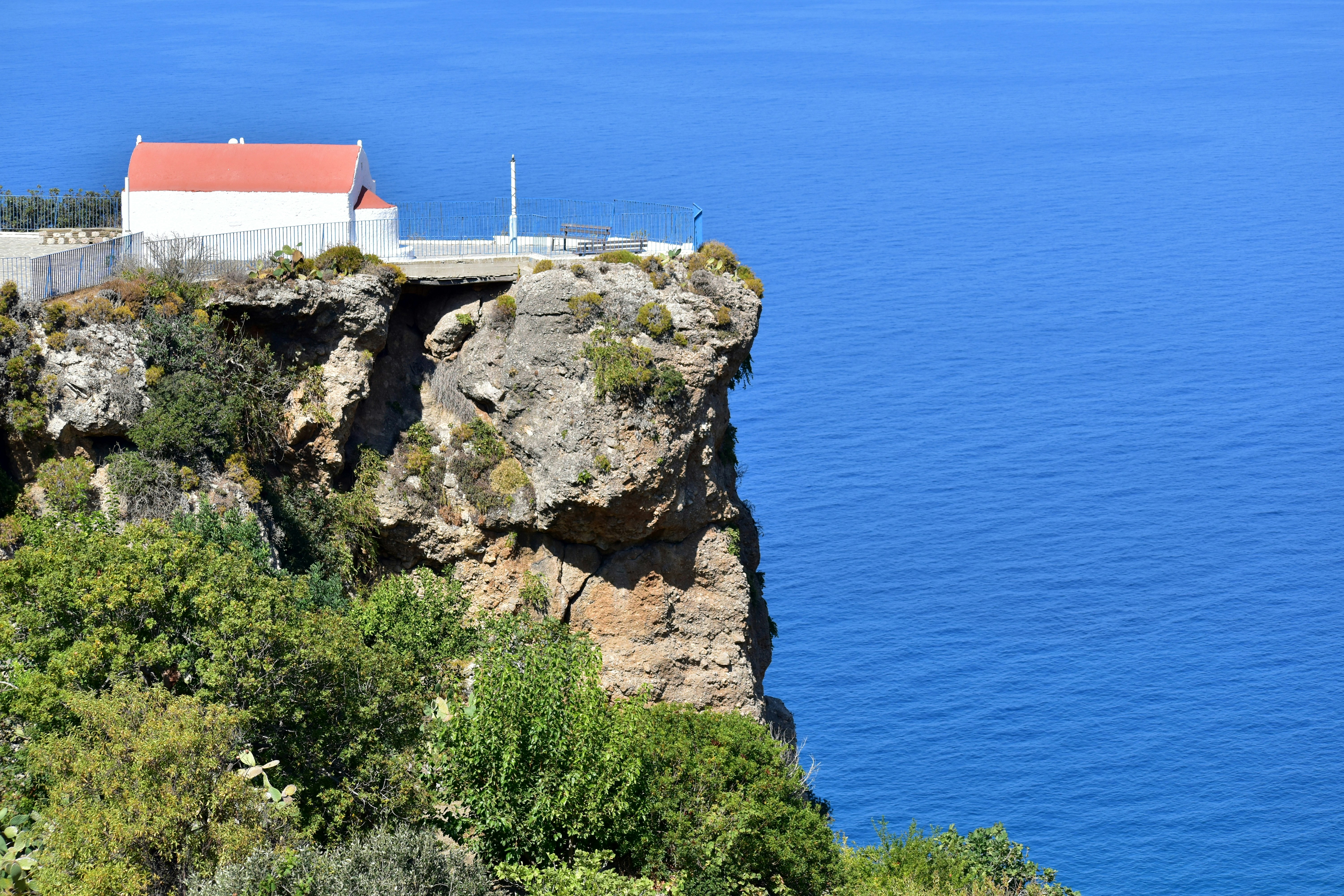 Cliffside Terrace: A White-walled Pier Beside a Red-Topped Shelter overlooking the Blue Expanse