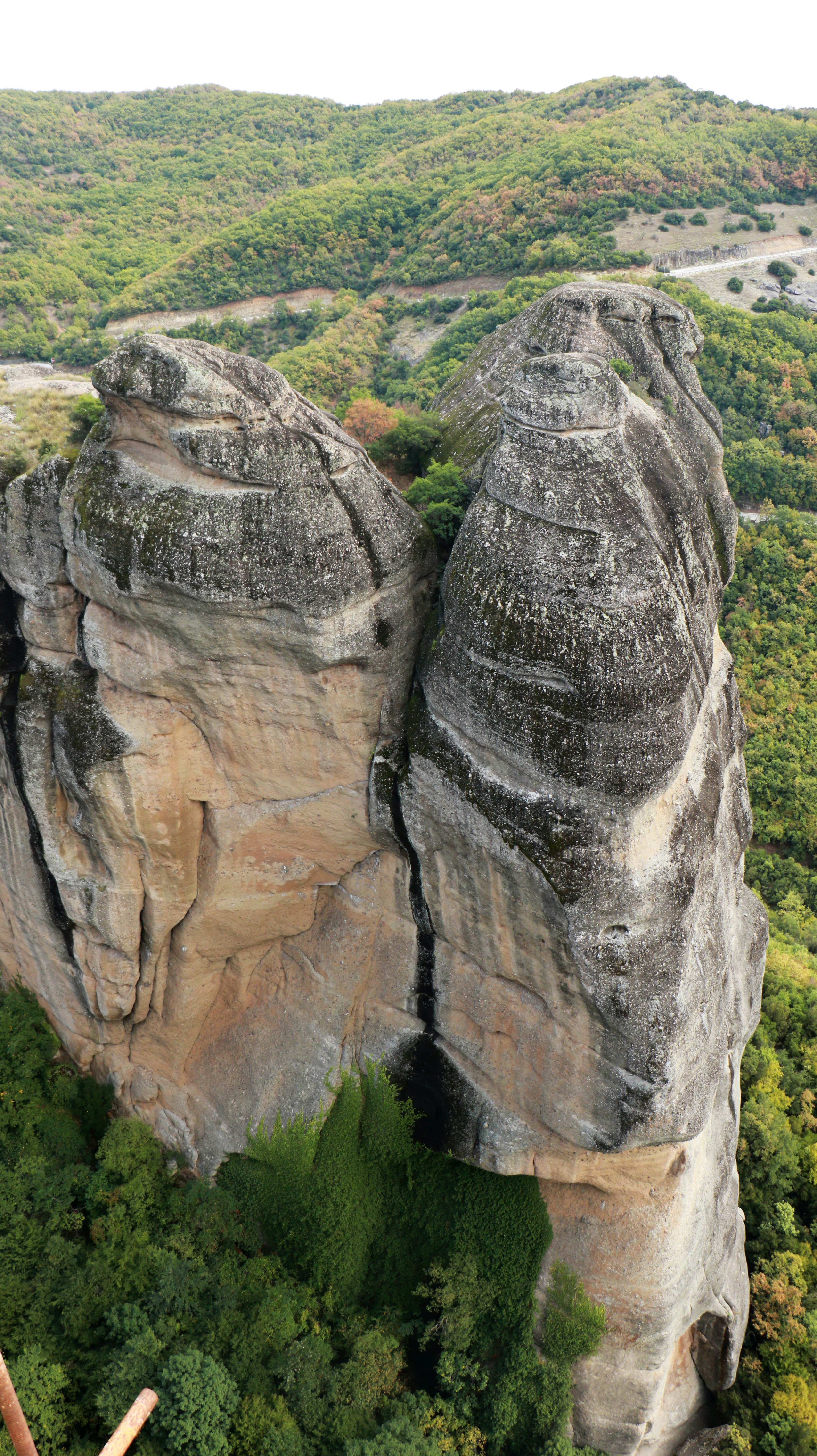 Stone Sentinels: Twin Monolithic Spires Rising from a Verdant Cliff