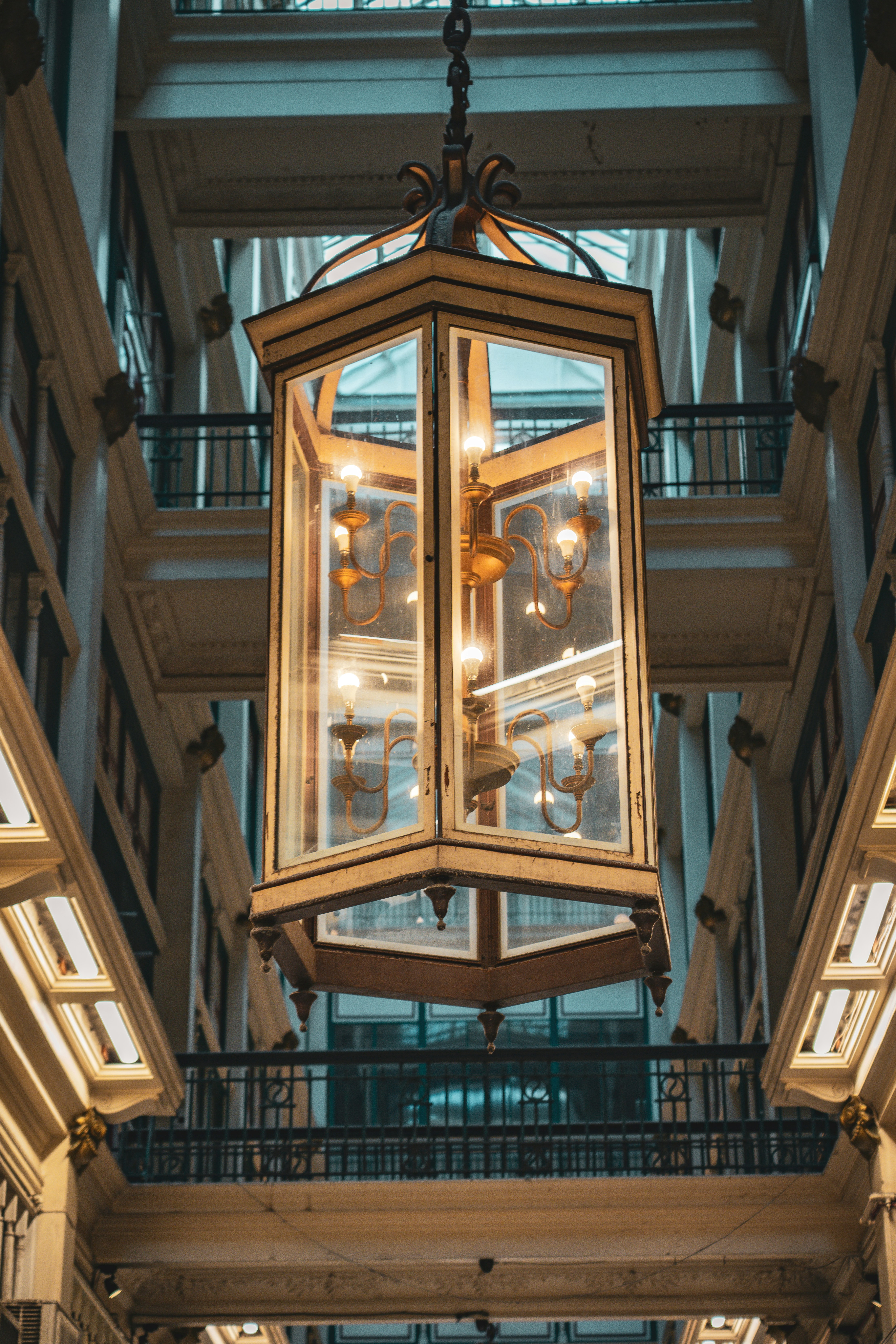 Ornate Lantern Pendant Casting Warm Glow Through Glass Facade