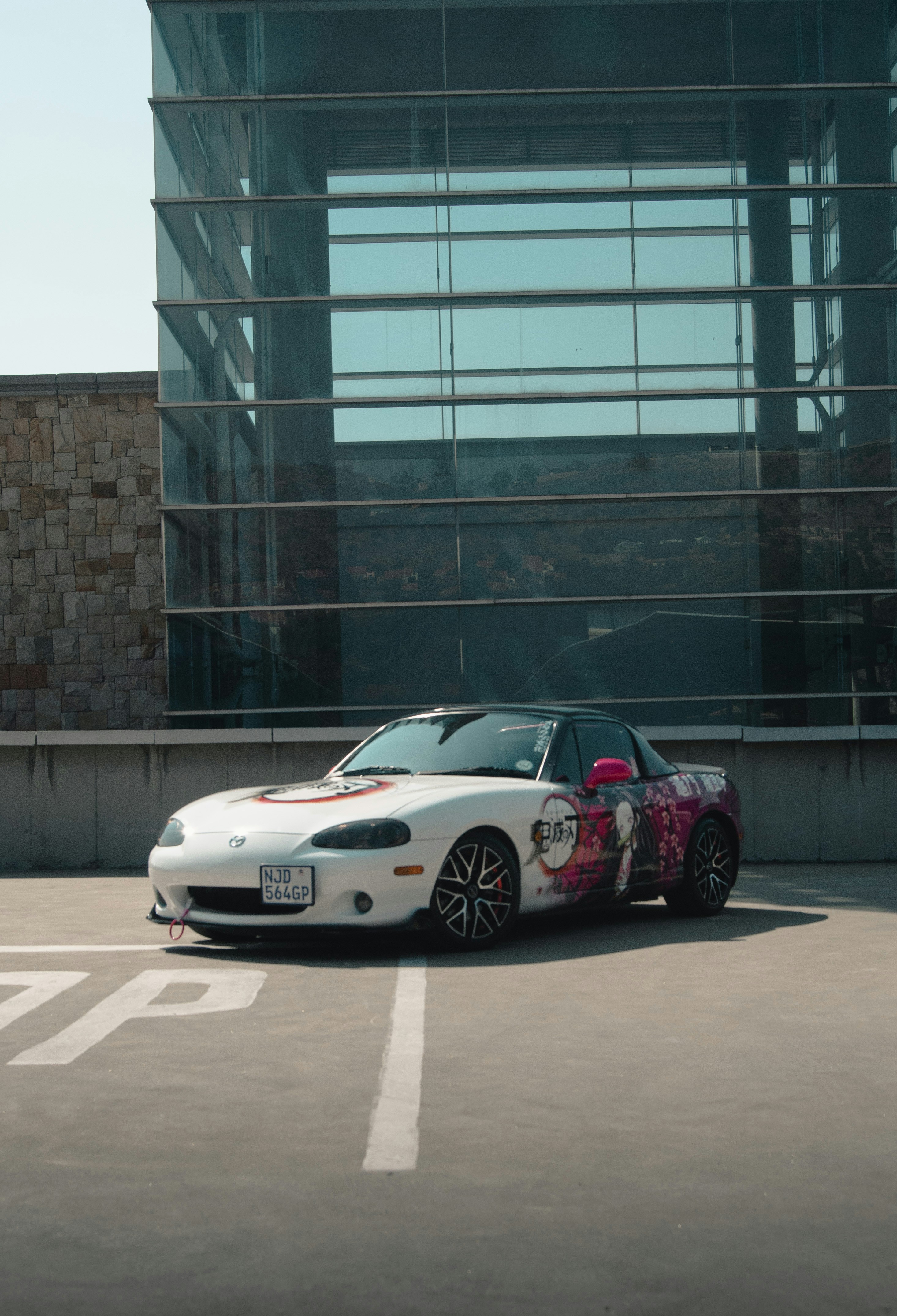 Graceful White Roadster Anchored by Glass Facade