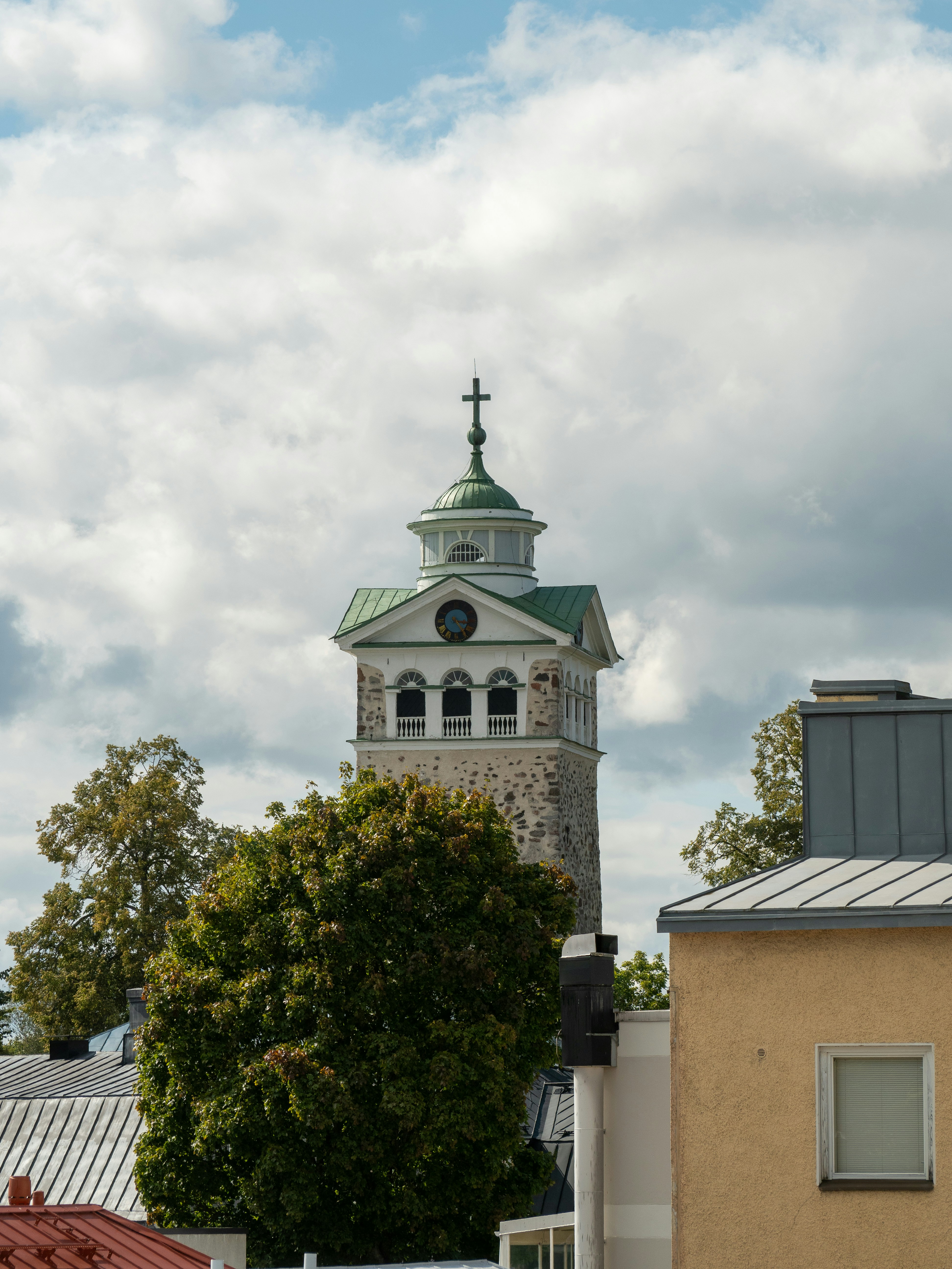 Verdant-Capped Clocktower Reaches the Sky Over Quiet Streets