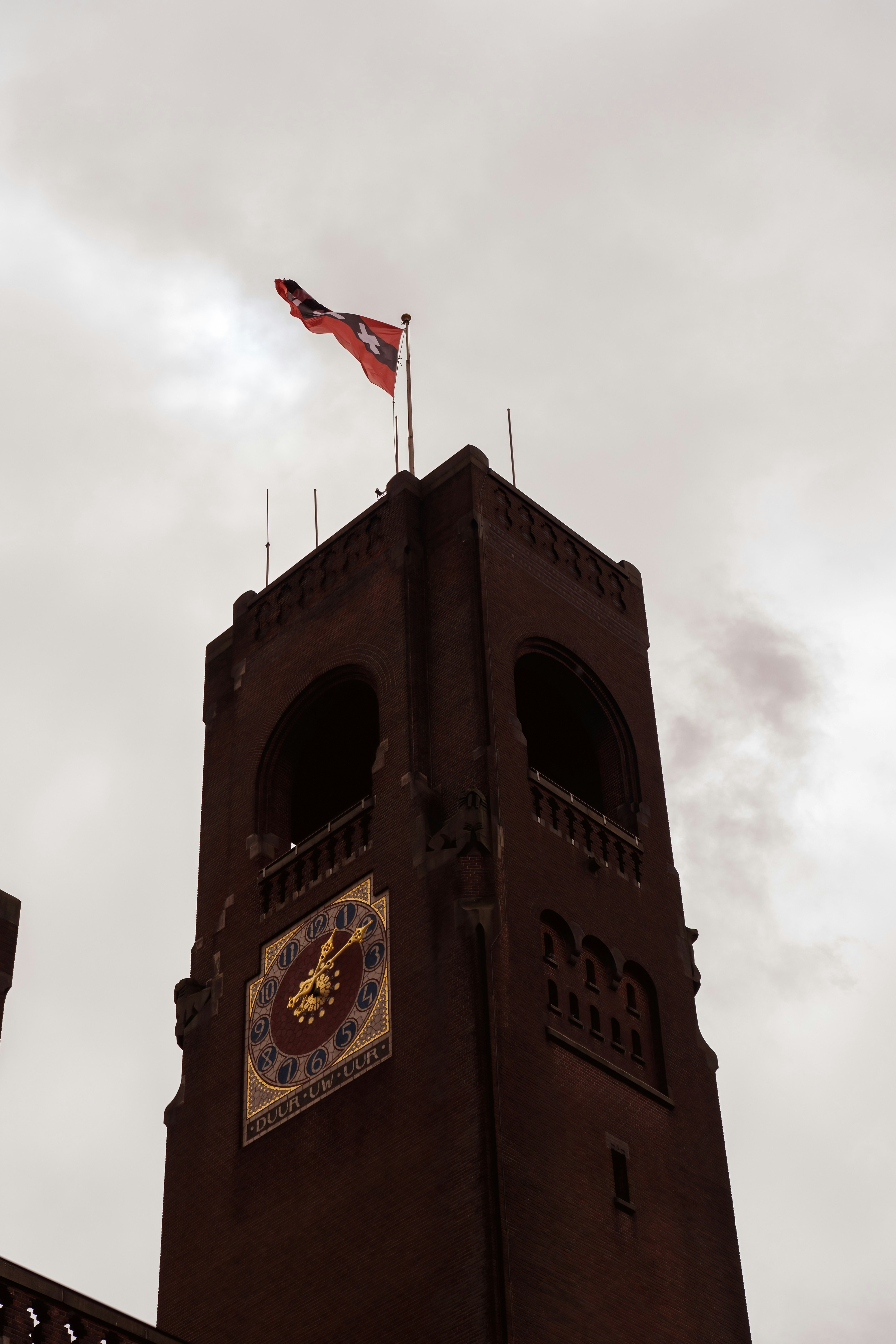 Swiss Flag Over a Brick Clock Tower Under a Moody Sky