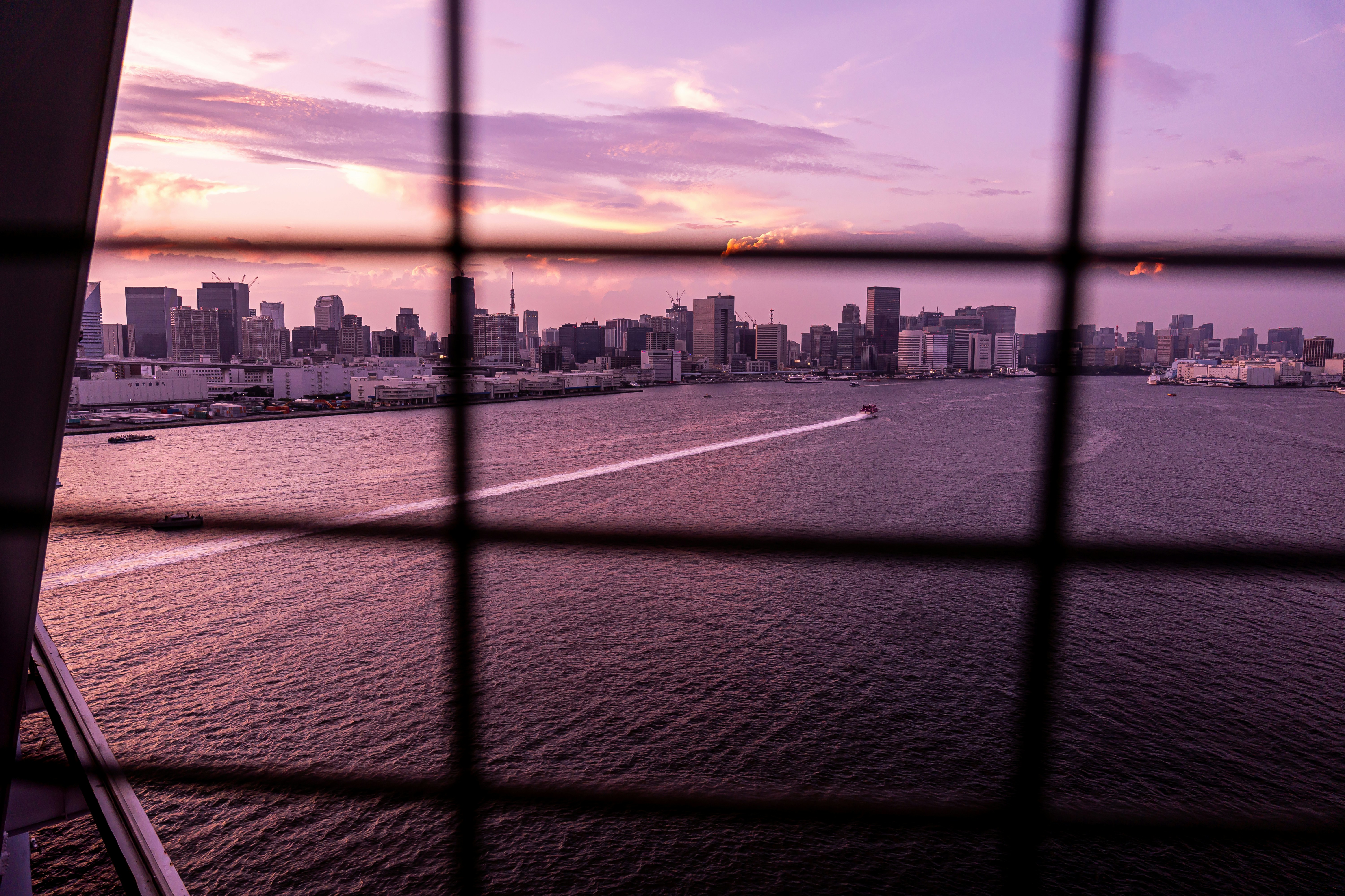 Sunset Over the Harbor Framed by a Grid of Window Bars