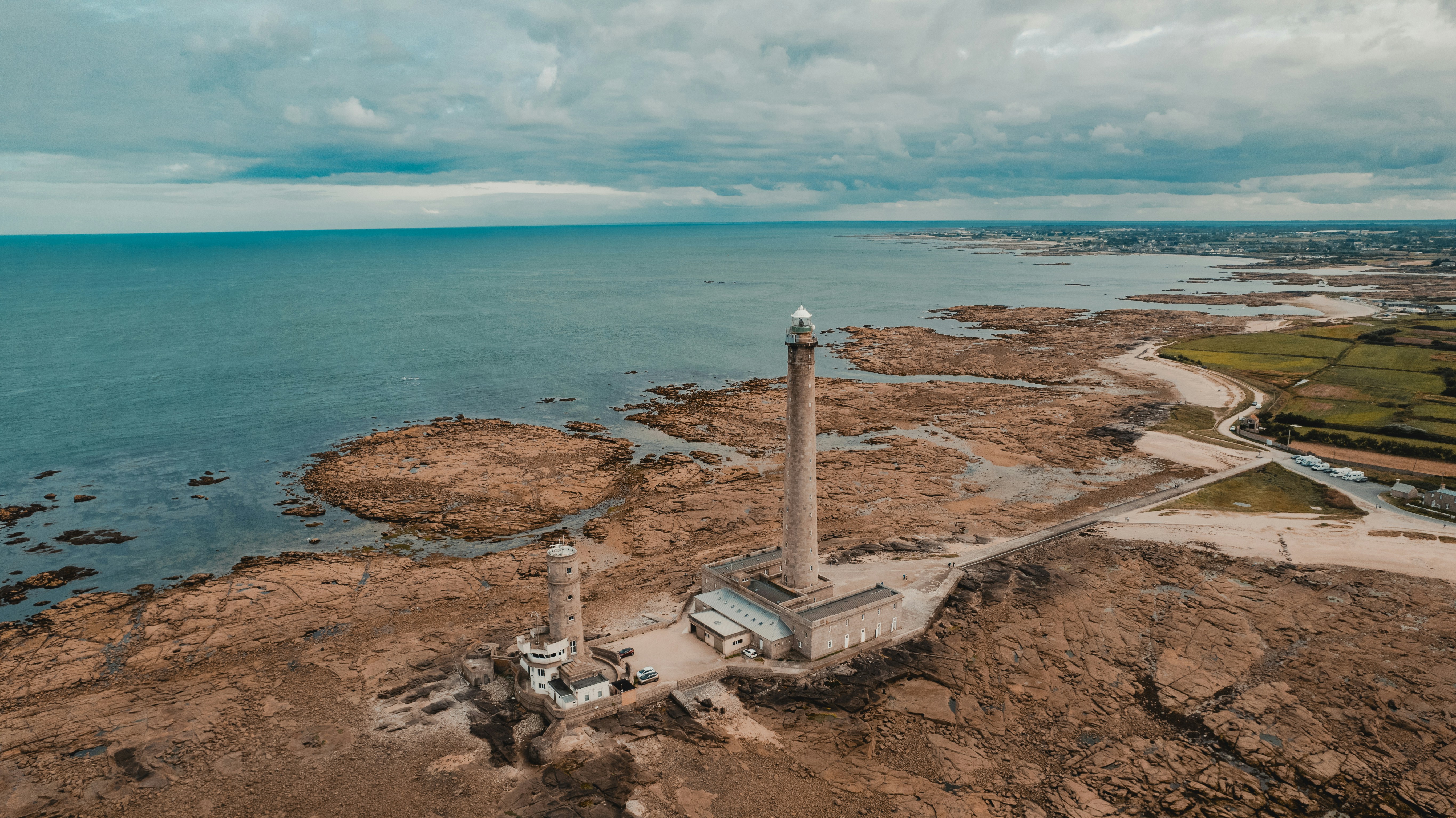 Aerial view of a power plant's towers standing on a rugged coastline with the ocean in the background.