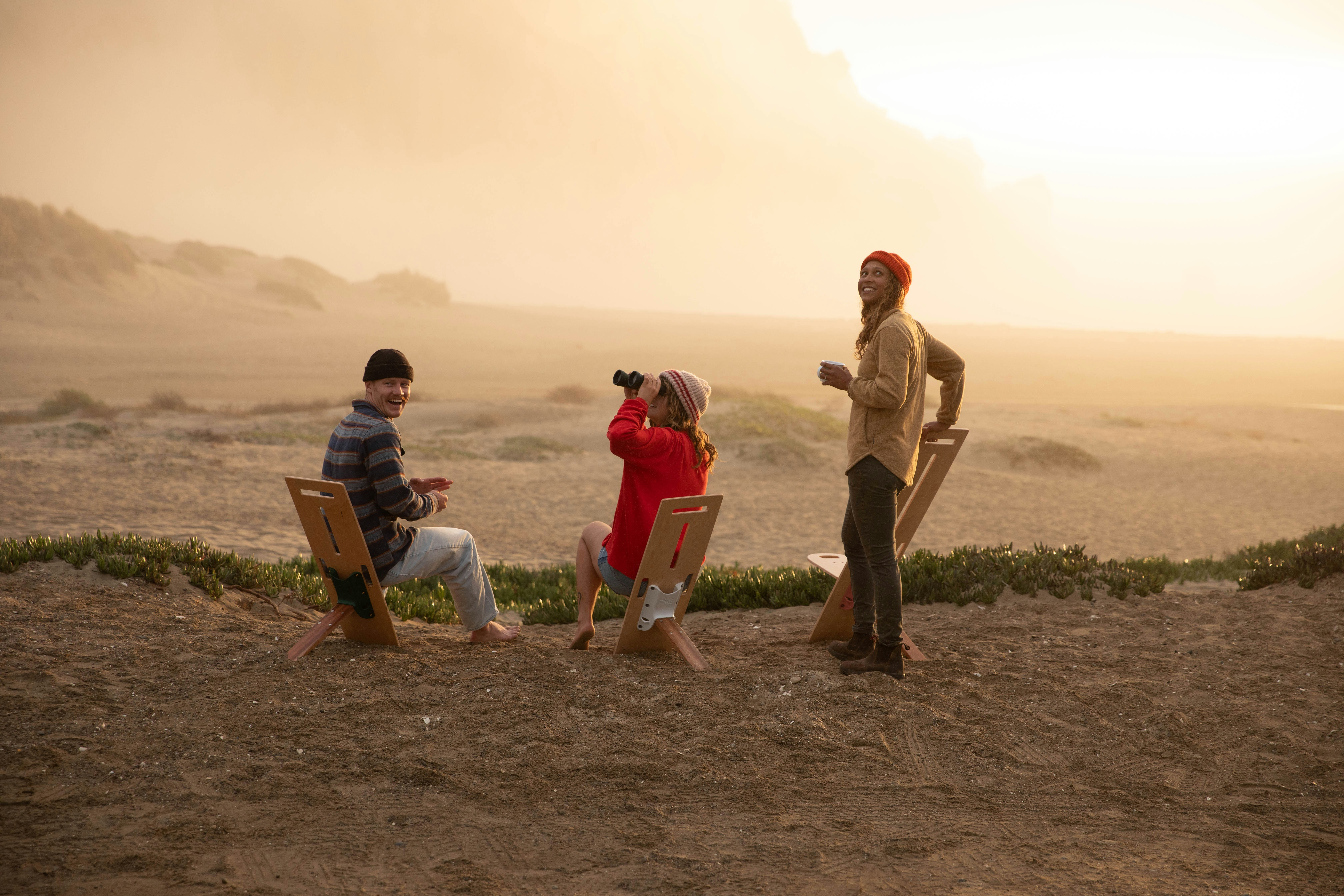 Friends watch the sun set on the beach in Oregon on Trippy Chairs