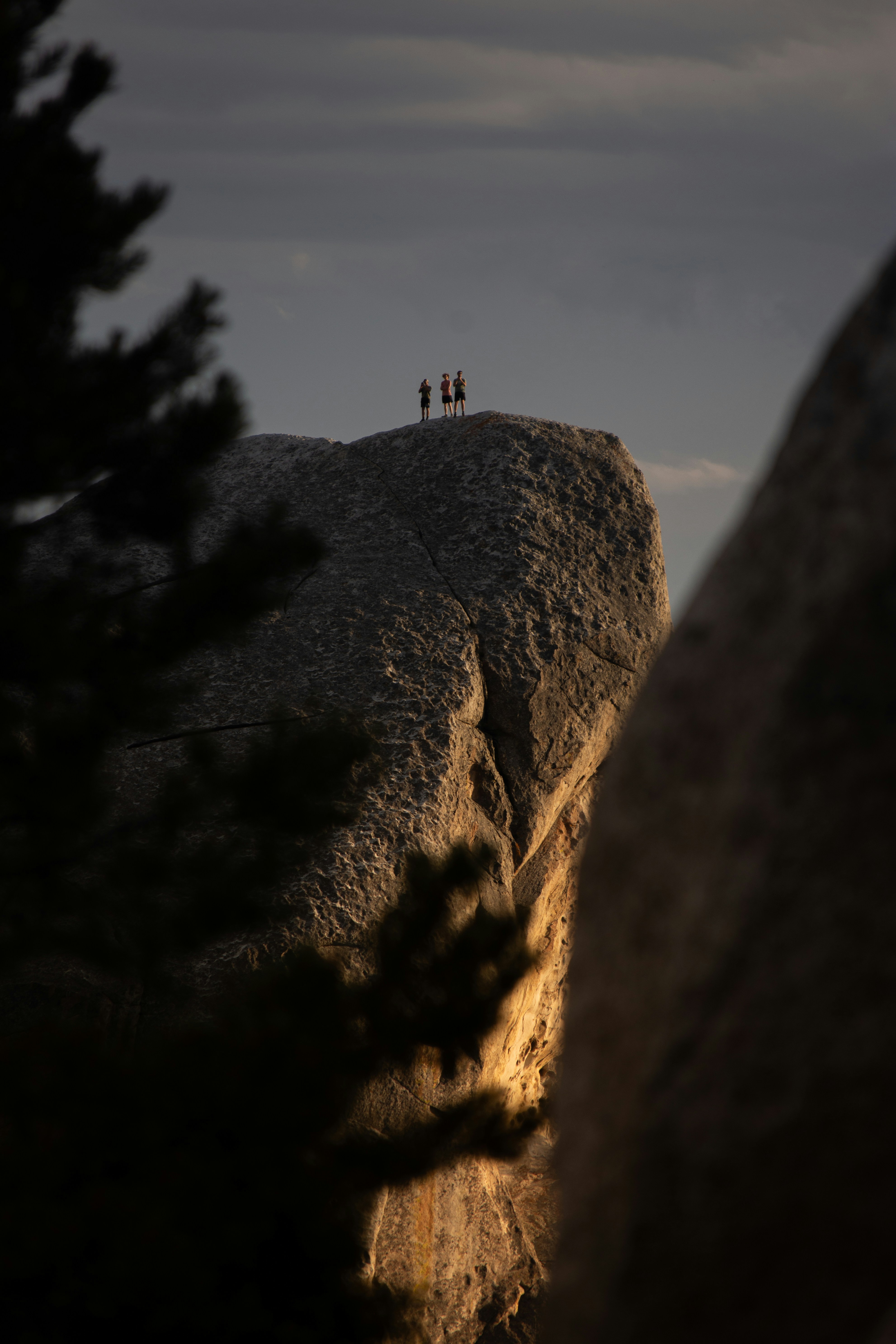 Gloaming Crest: Three silhouettes on a granite sentinel at dusk