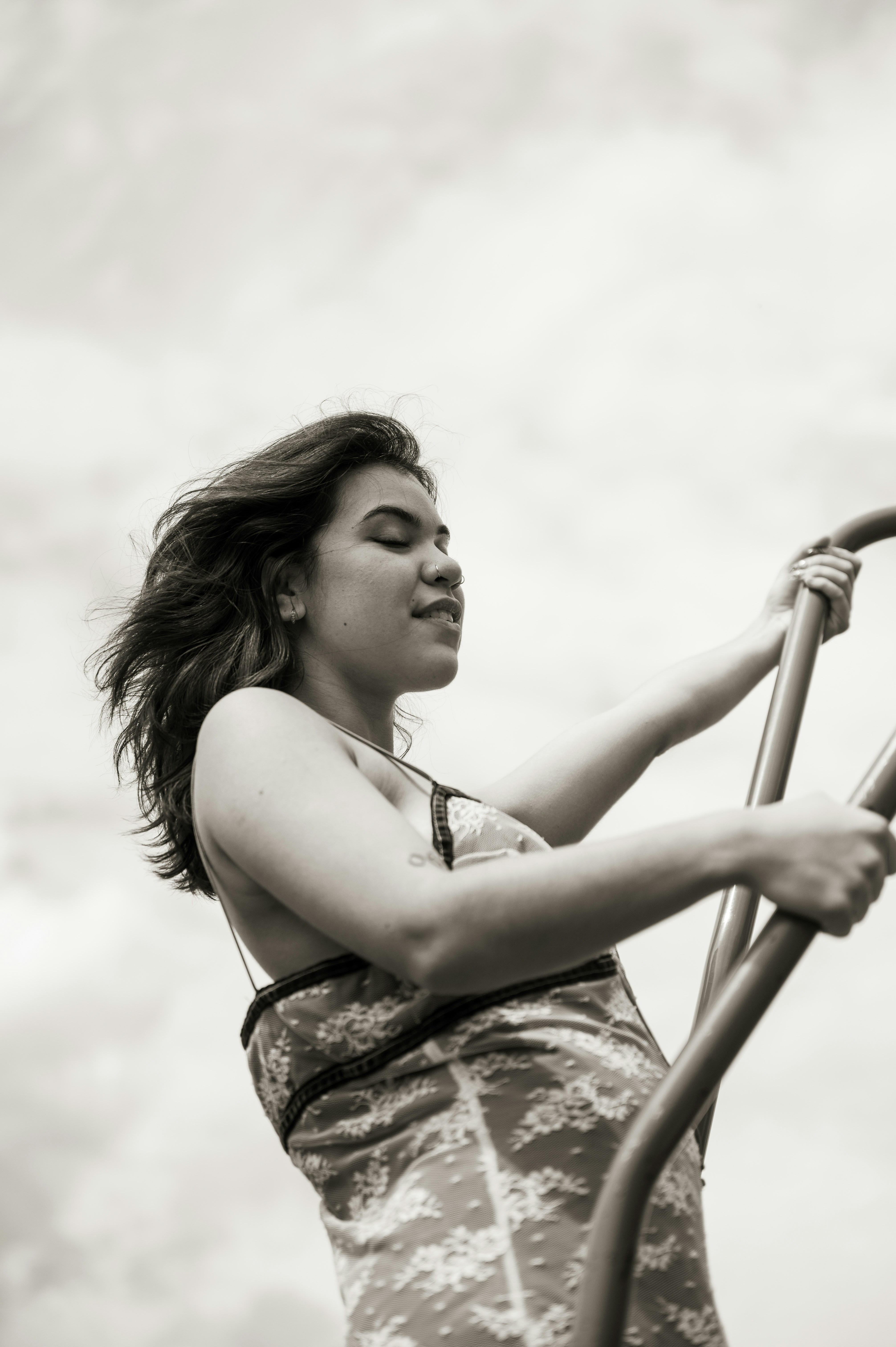 Lifted in the Wind: a portrait atop a playground frame against a soft sky