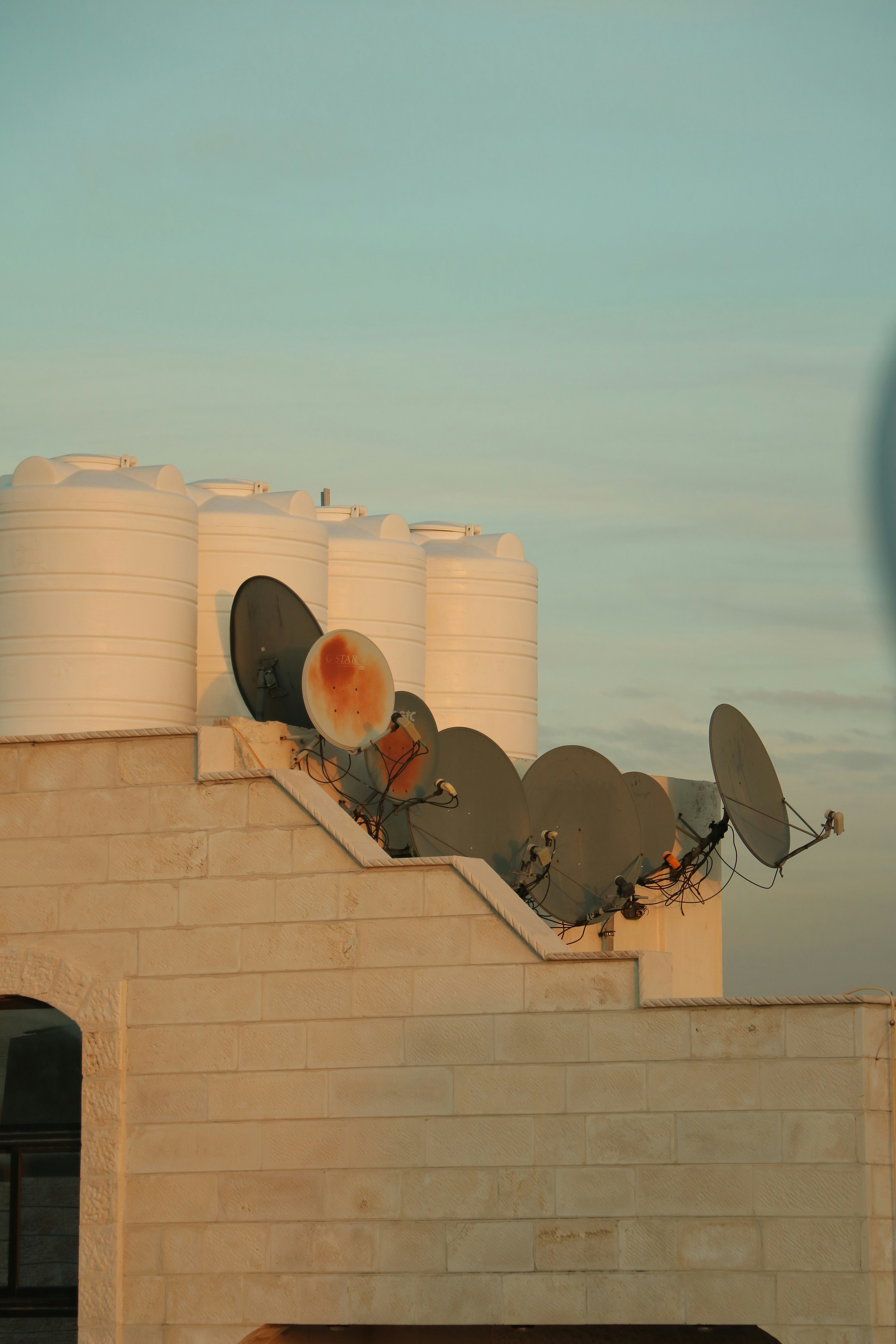 Rooftop Array: Dishes and Cylinders Against a pastel Sky