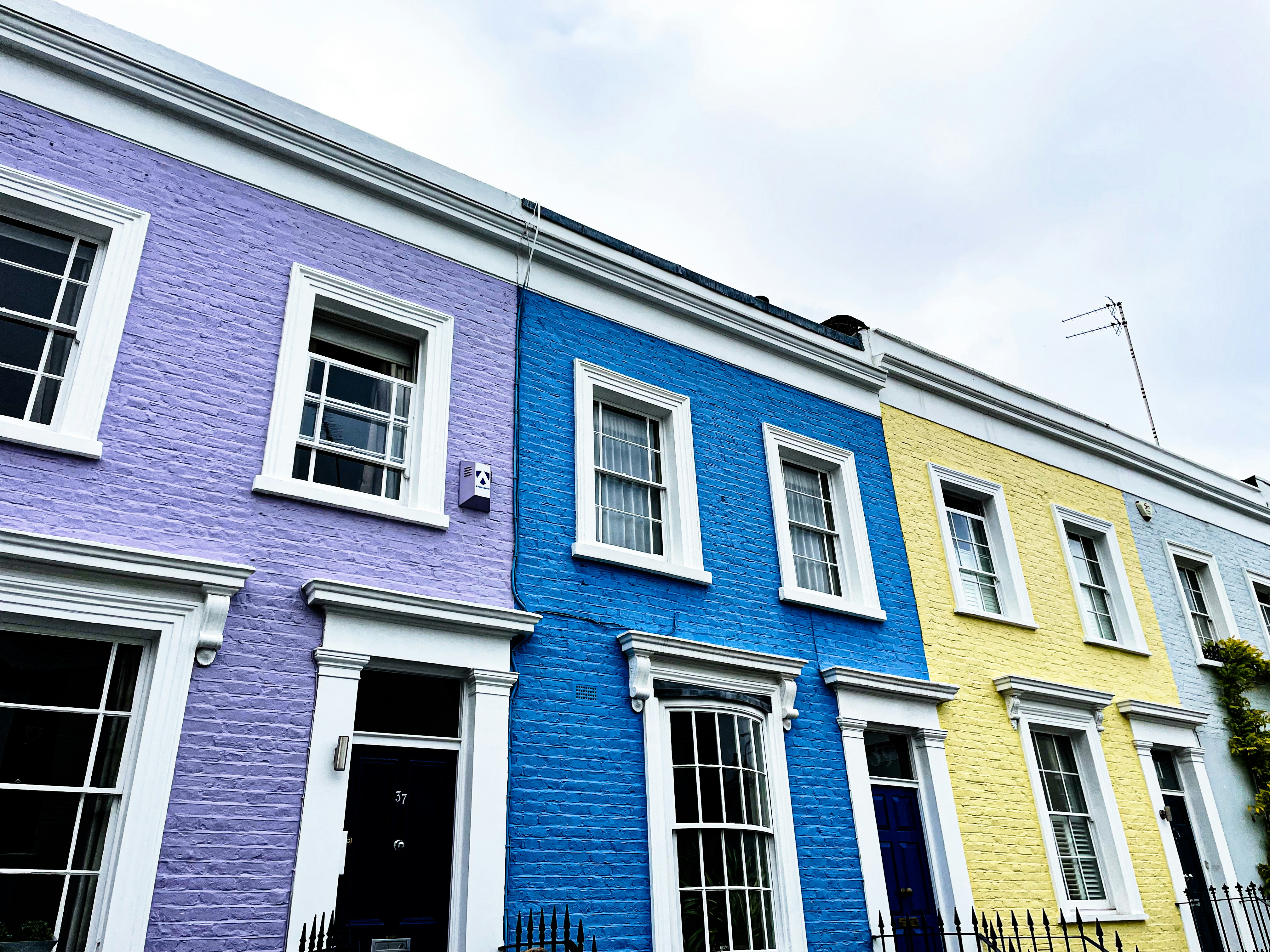 A row of multi - colored houses with white windows photo – Free ...