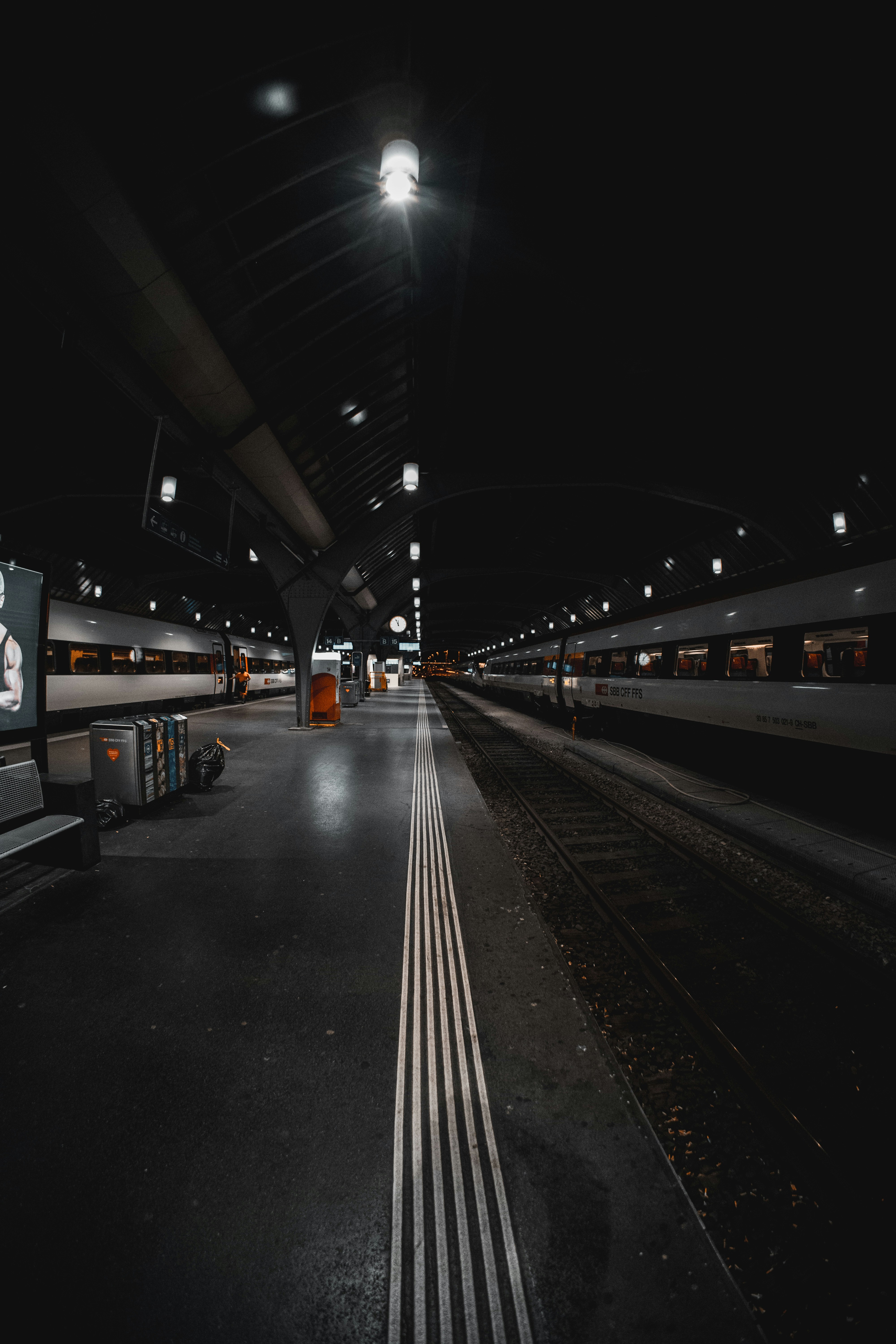 A dimly lit train station with benches and lights photo – Free ...