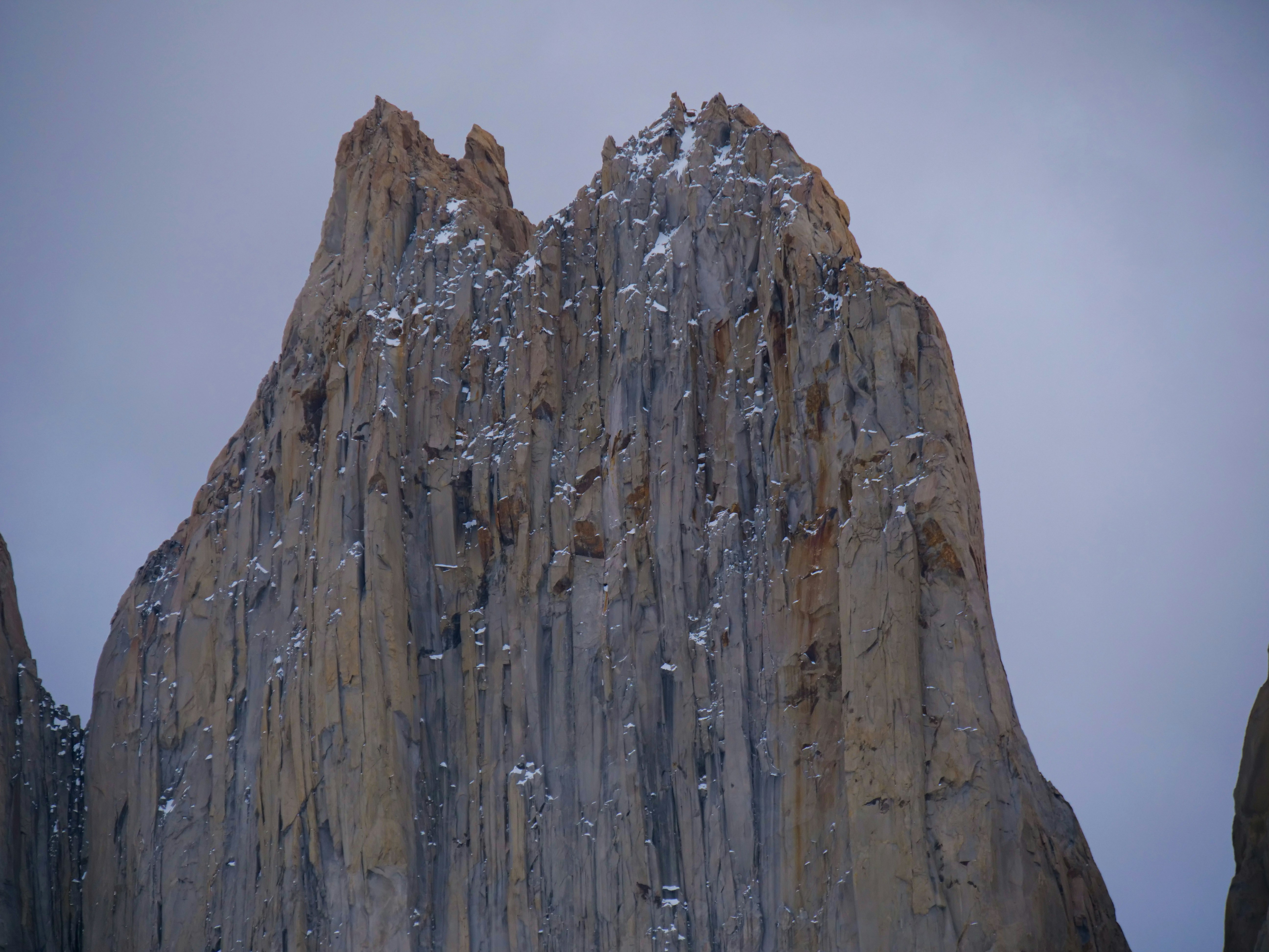 Jagged Sentinel: Snow-kissed Peak Piercing a Moody Sky