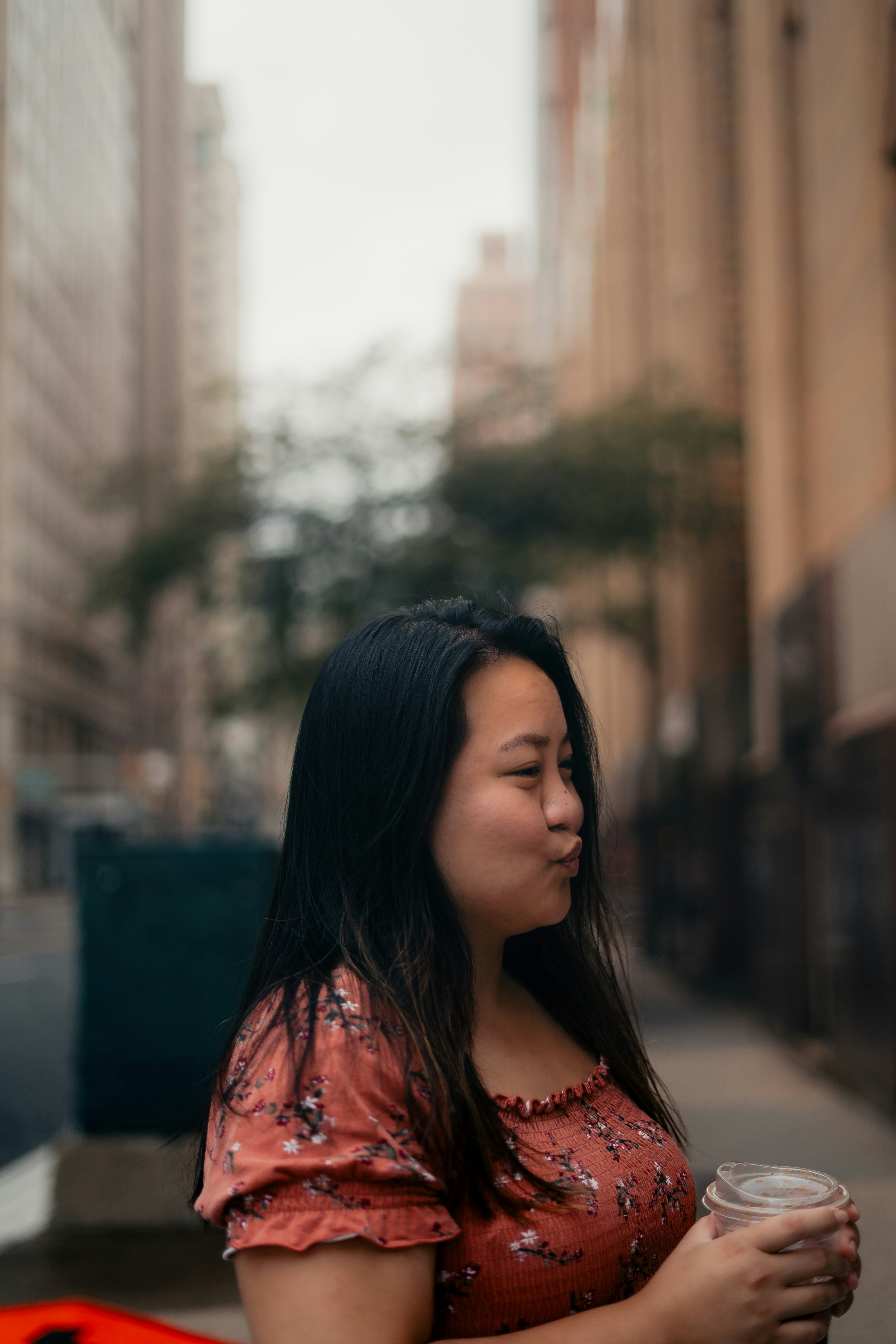 Sidewalk Quietude: Portrait of a Woman with a Drink in Soft Focus