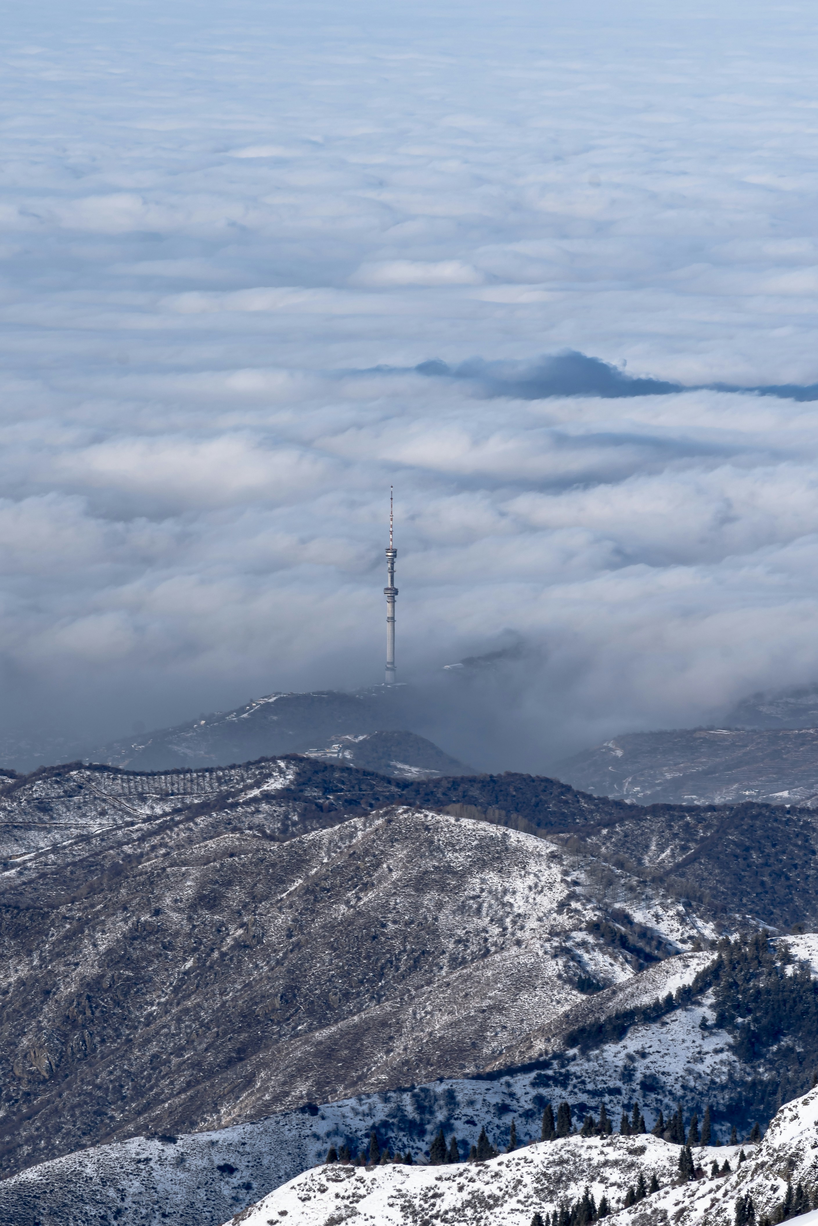 Cloud-veiled Summit: A Lone Antenna Rises Over Snow-kissed Peaks