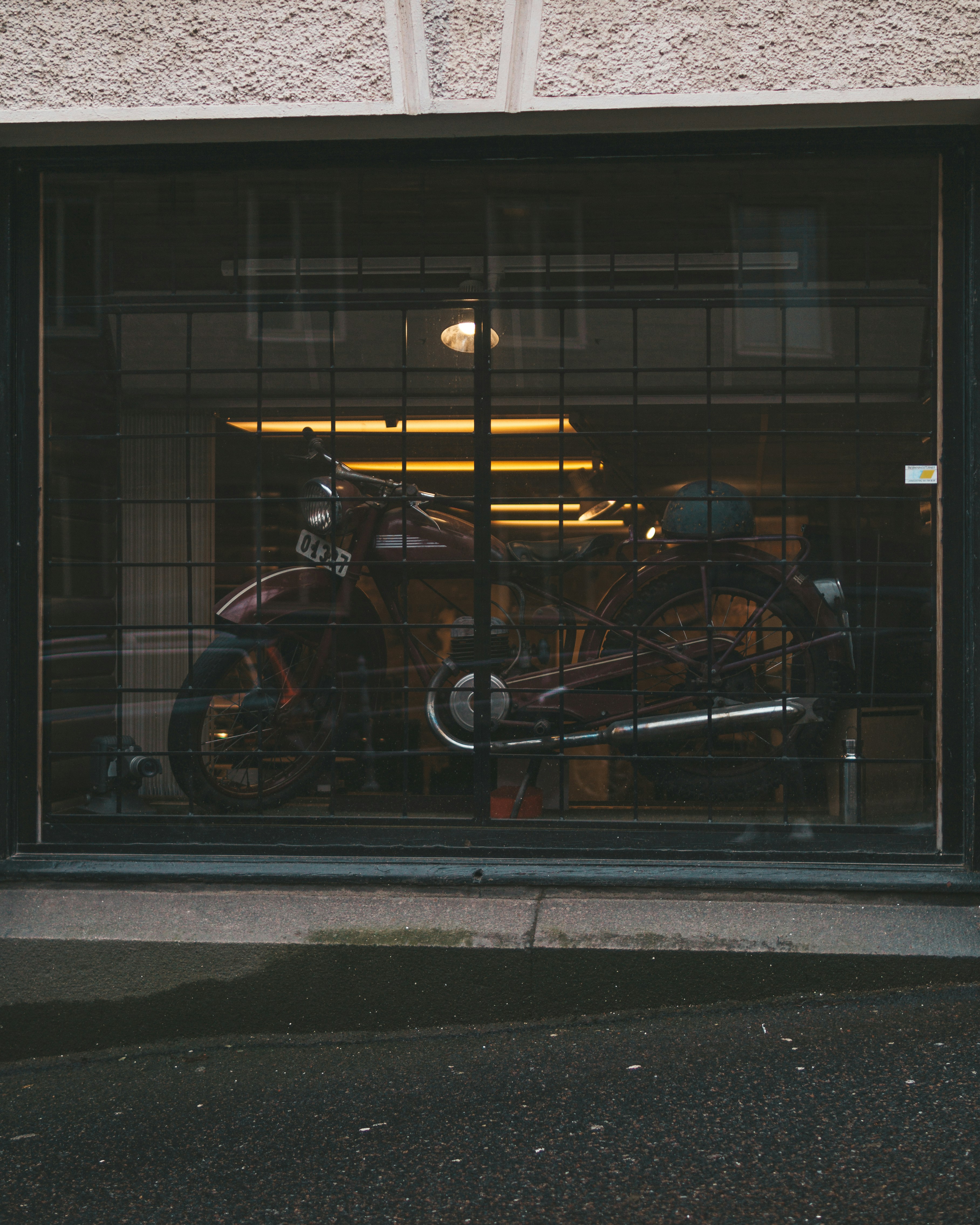 Chrome in a Cage: A Vintage Motorcycle Housed Behind Gridded Glass