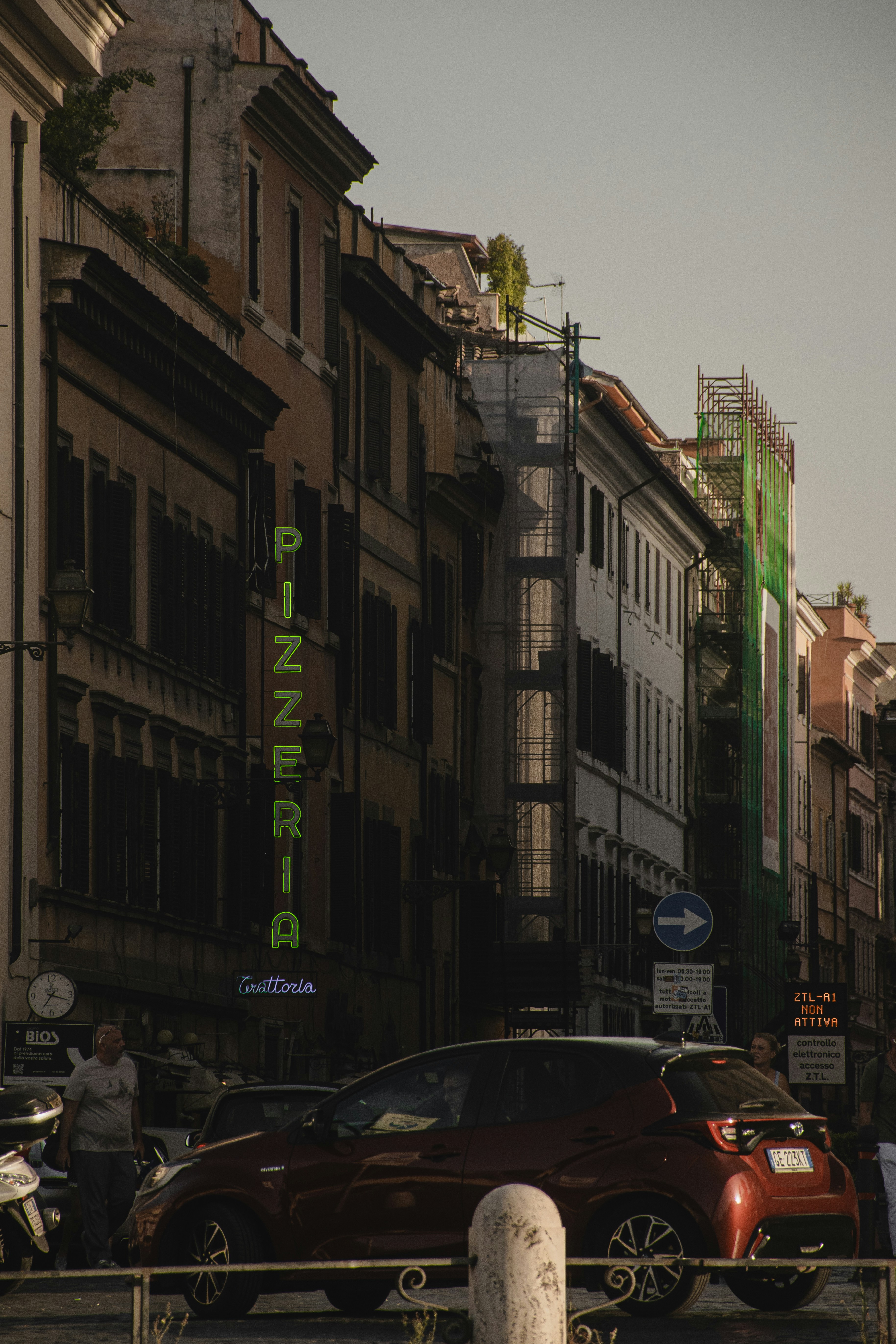 Green Neon Pizzeria Sign Illuminates a Narrow Street at Dusk