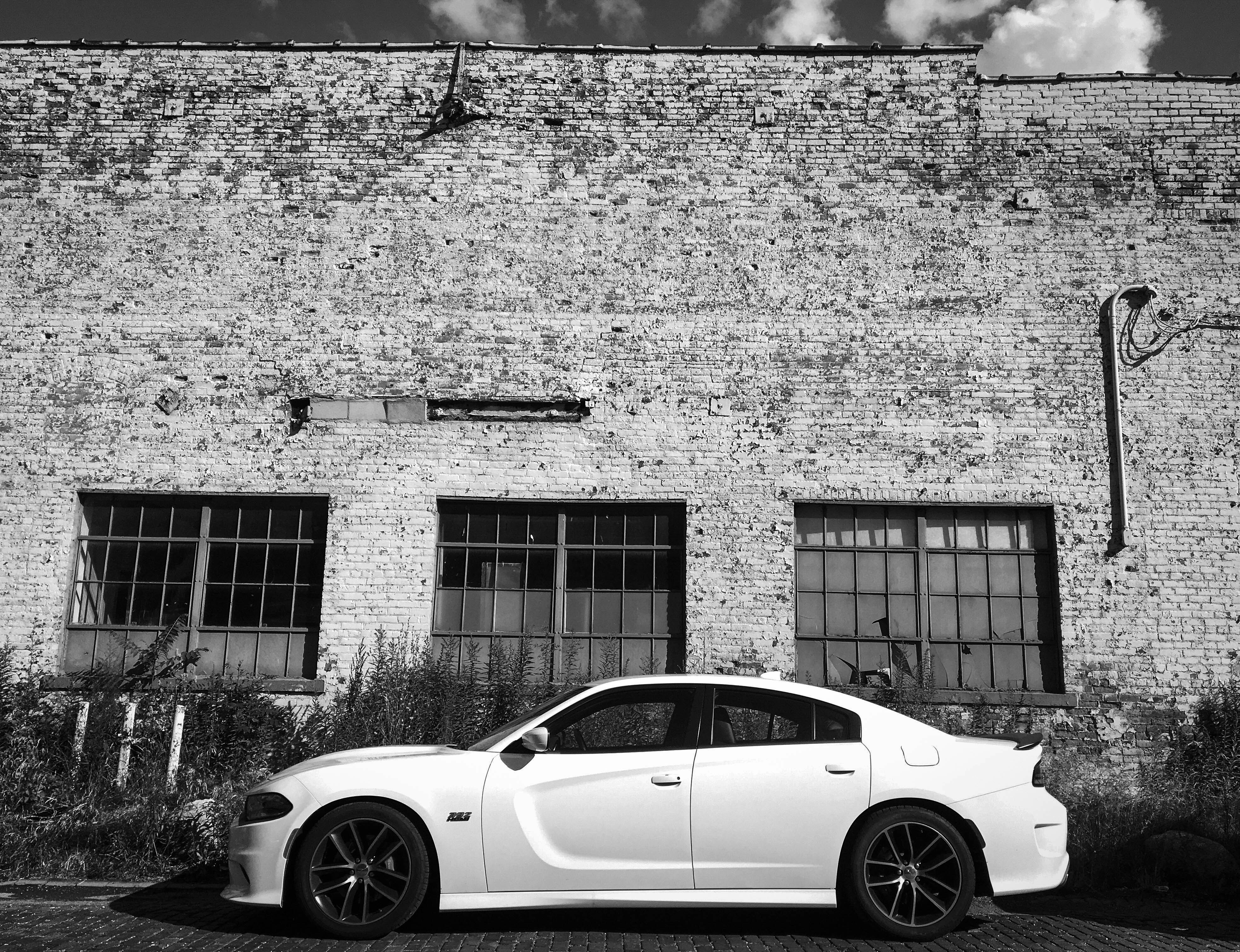 A white car parked in front of a brick building photo – Free Industrial ...
