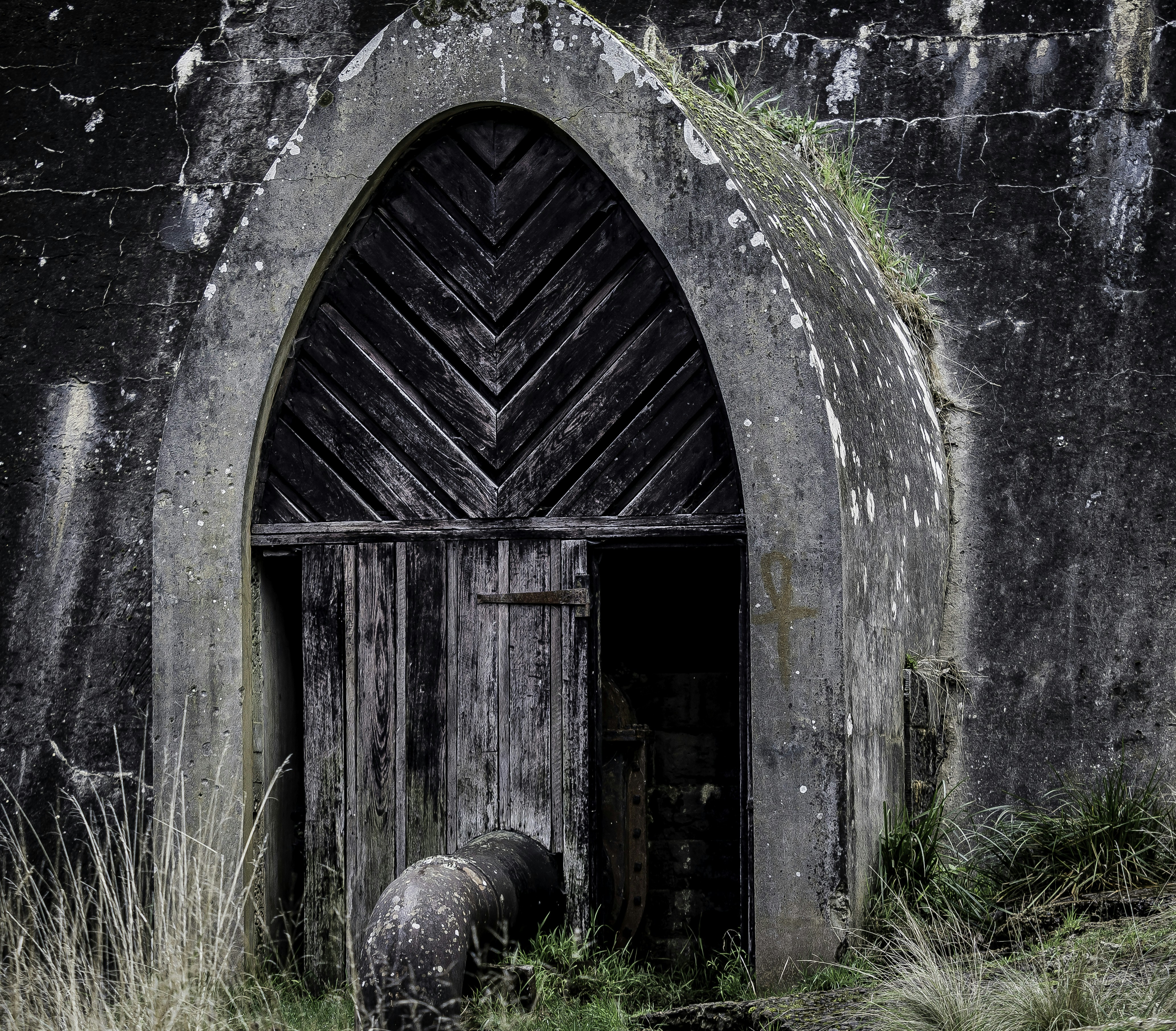 Moss-Covered Archway Framing a Weathered Vault Door