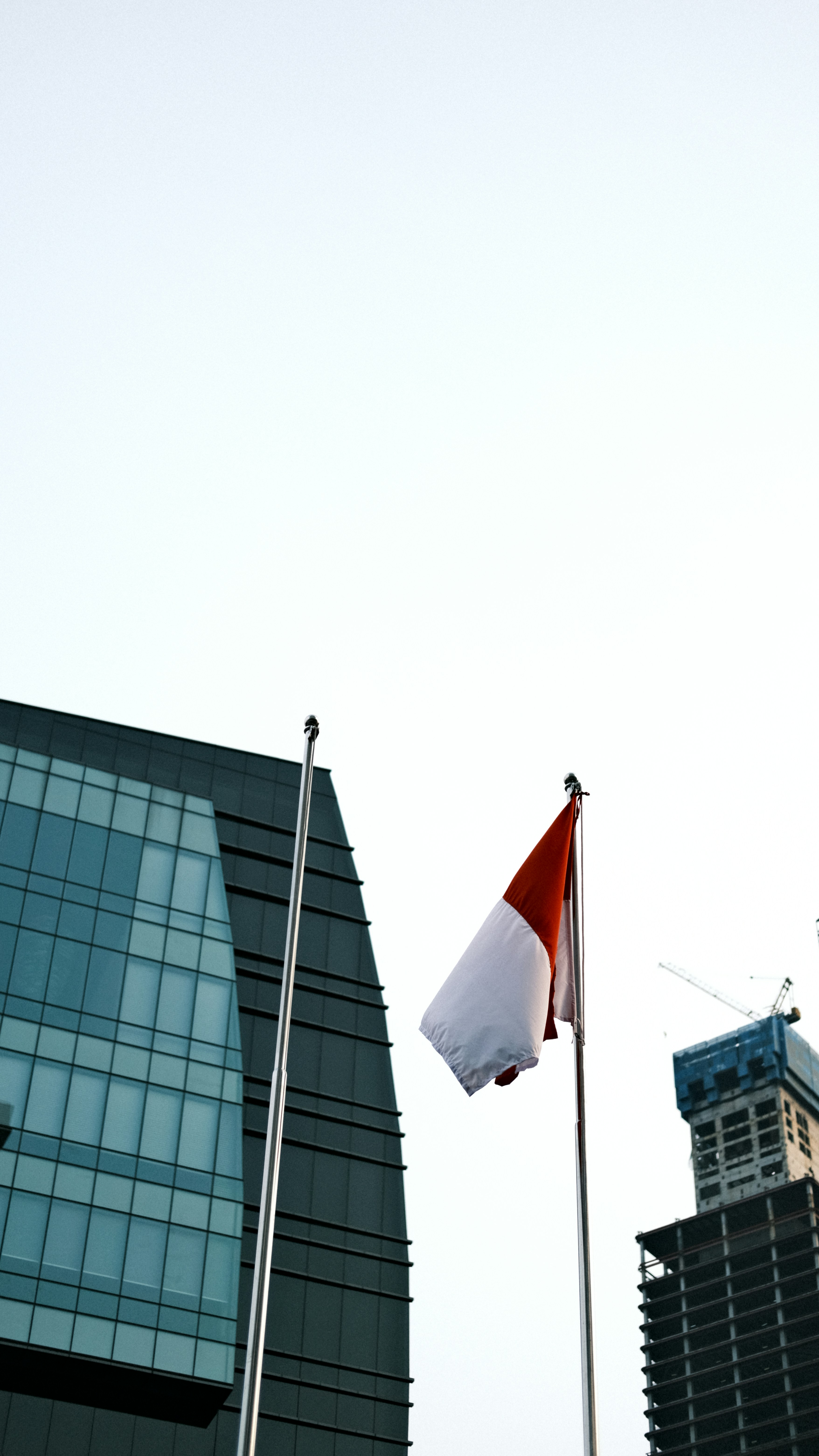 a red and white flag flying next to a tall building