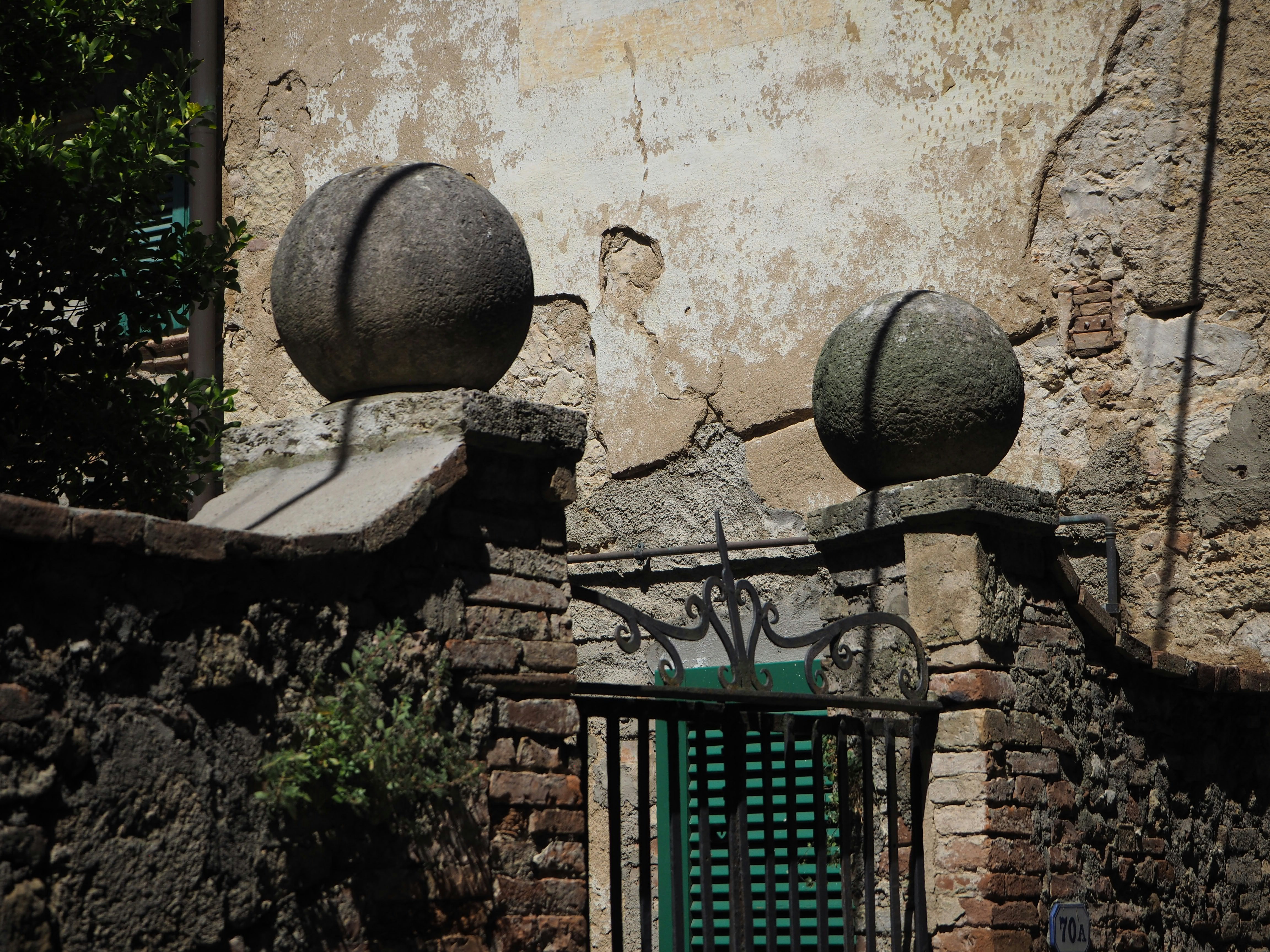 Weathered Gatekeepers: Round Stone Orbs Over a Worn Wall