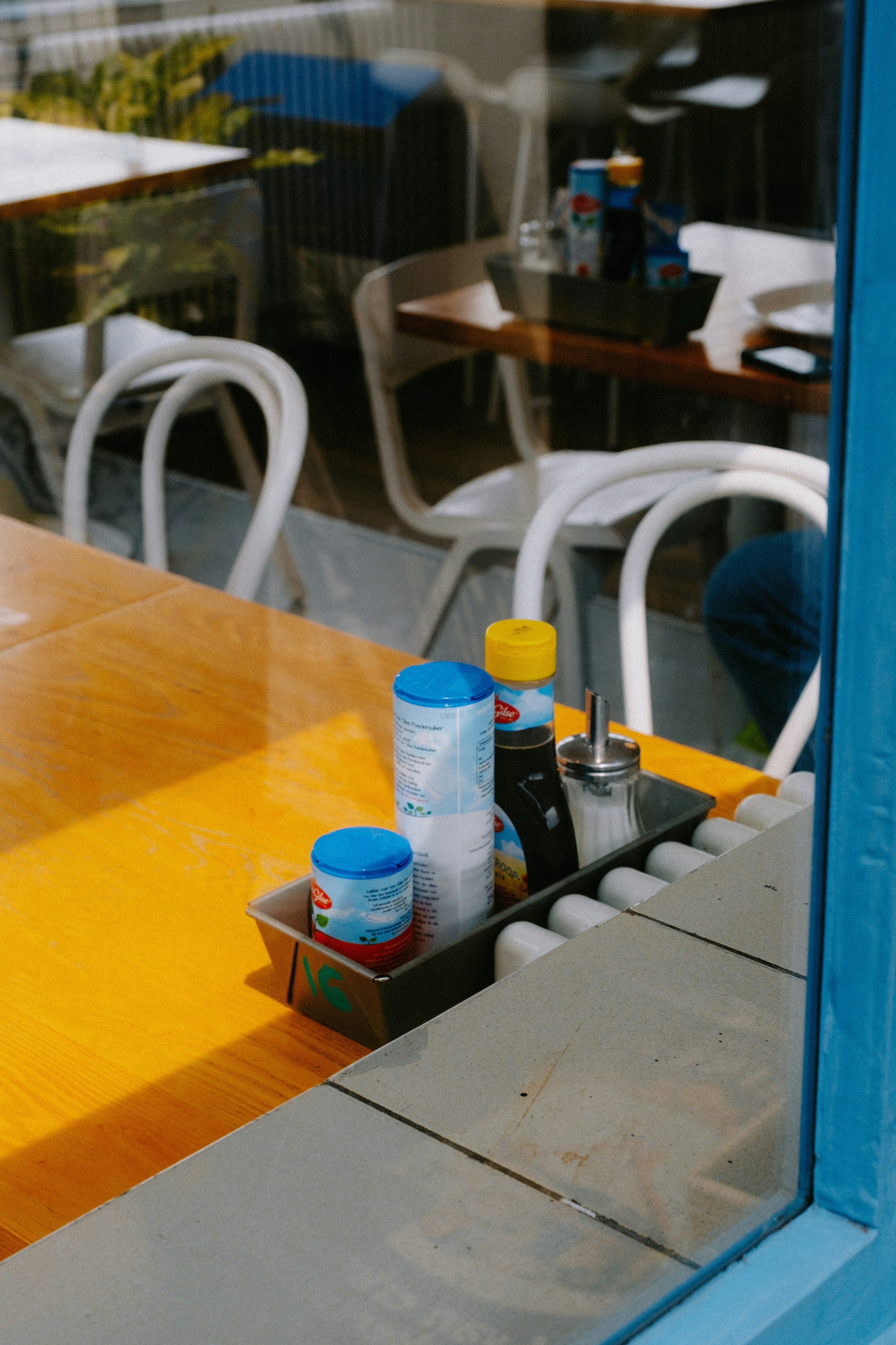 Sunlit Condiment Tray Anchors a Quiet Café Window Scene